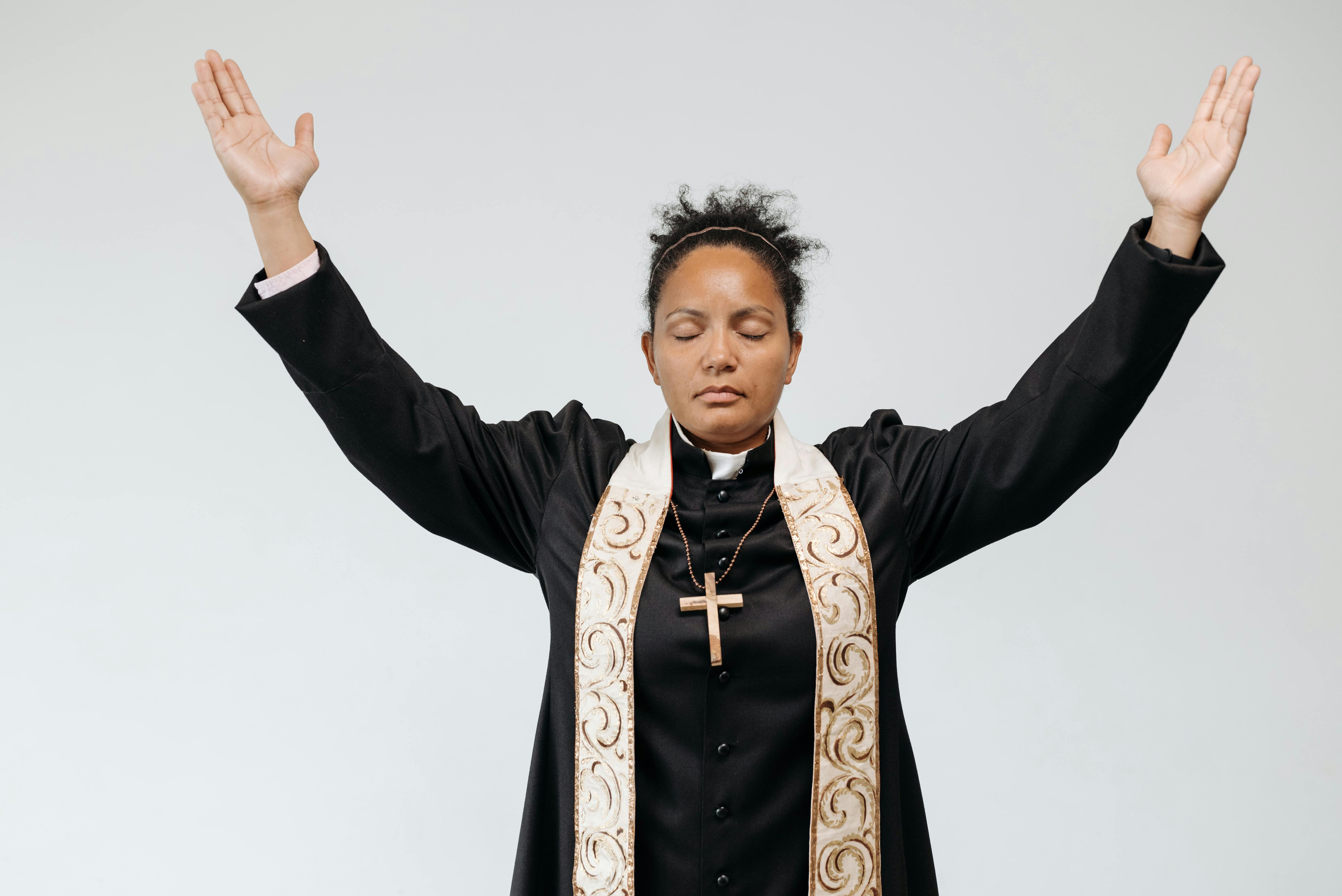 Female Christian Priest Praying with her Arms Raised · Free Stock Photo