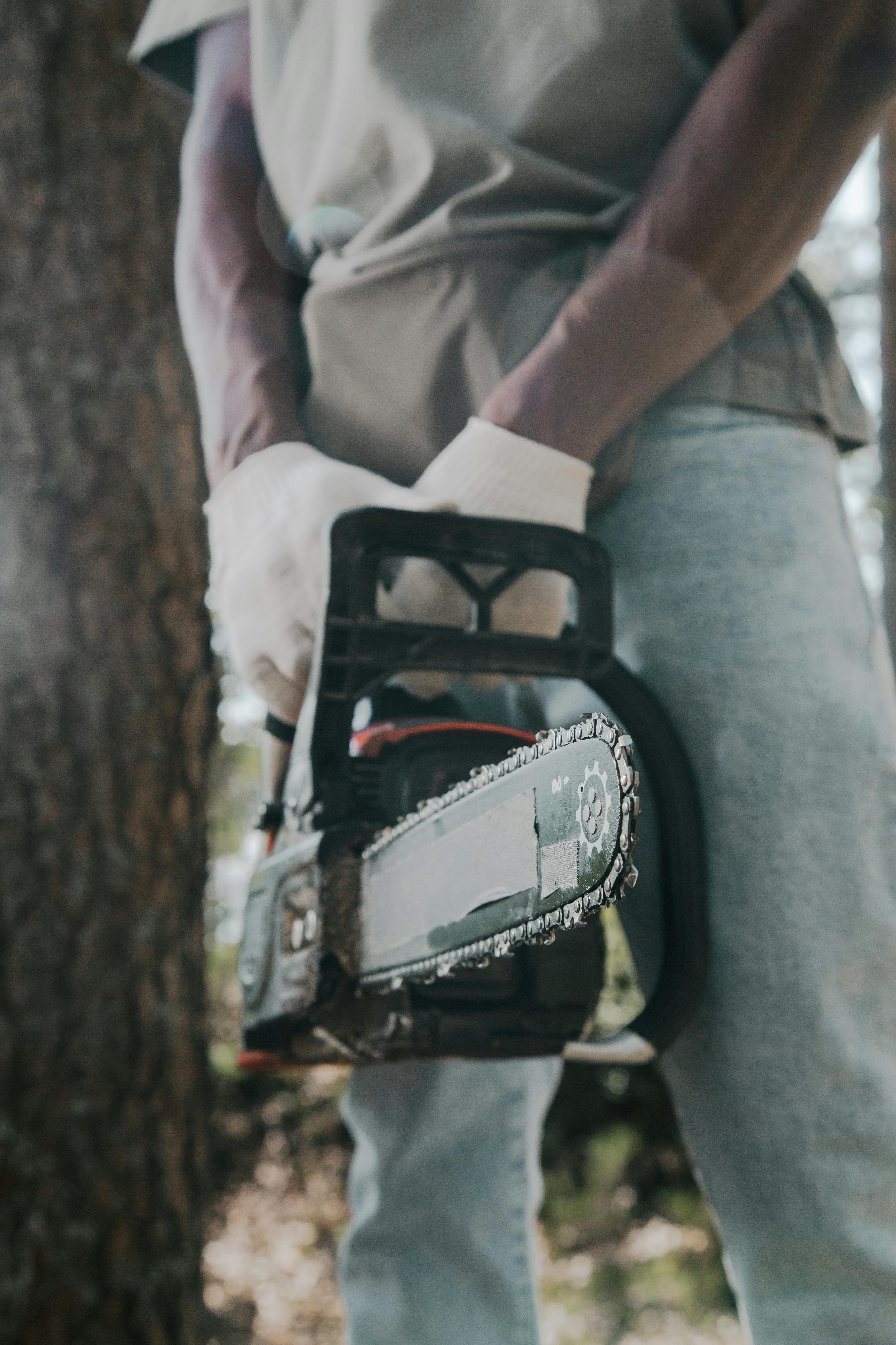 Person Standing and Holding a Chainsaw · Free Stock Photo