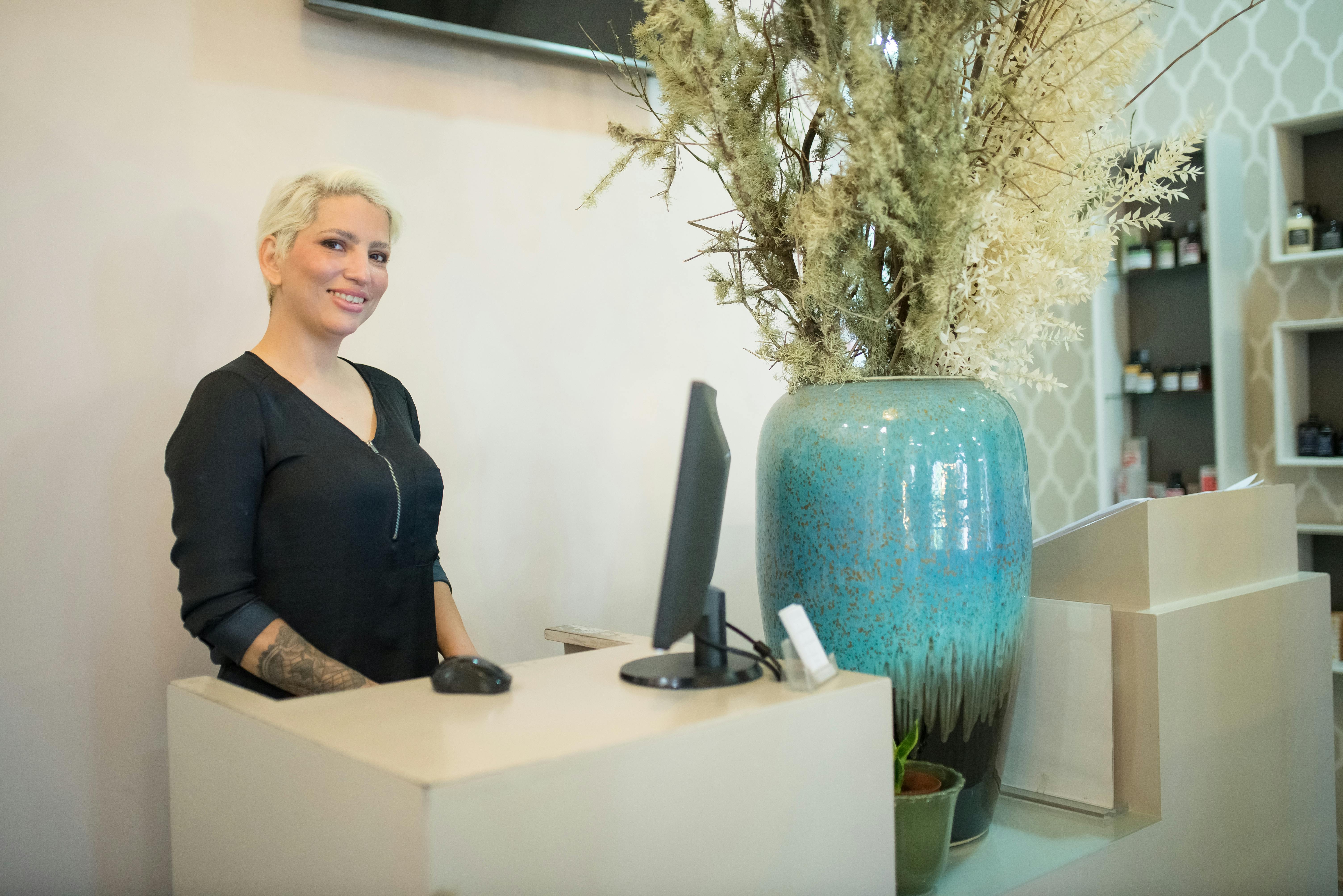 A Woman Standing on the Front Desk with Computer Monitor while Smiling ...