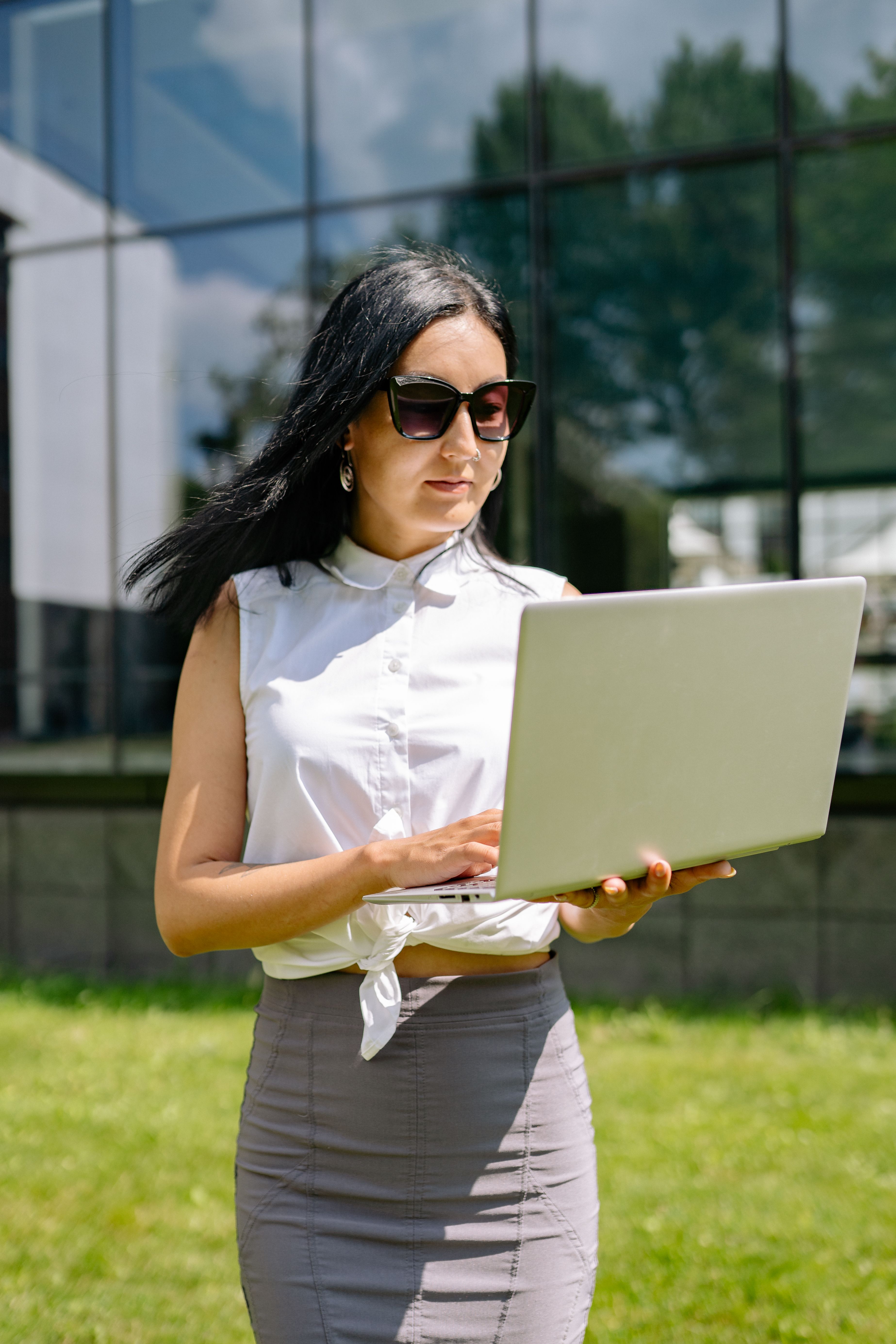 Woman Standing While Using a Laptop · Free Stock Photo
