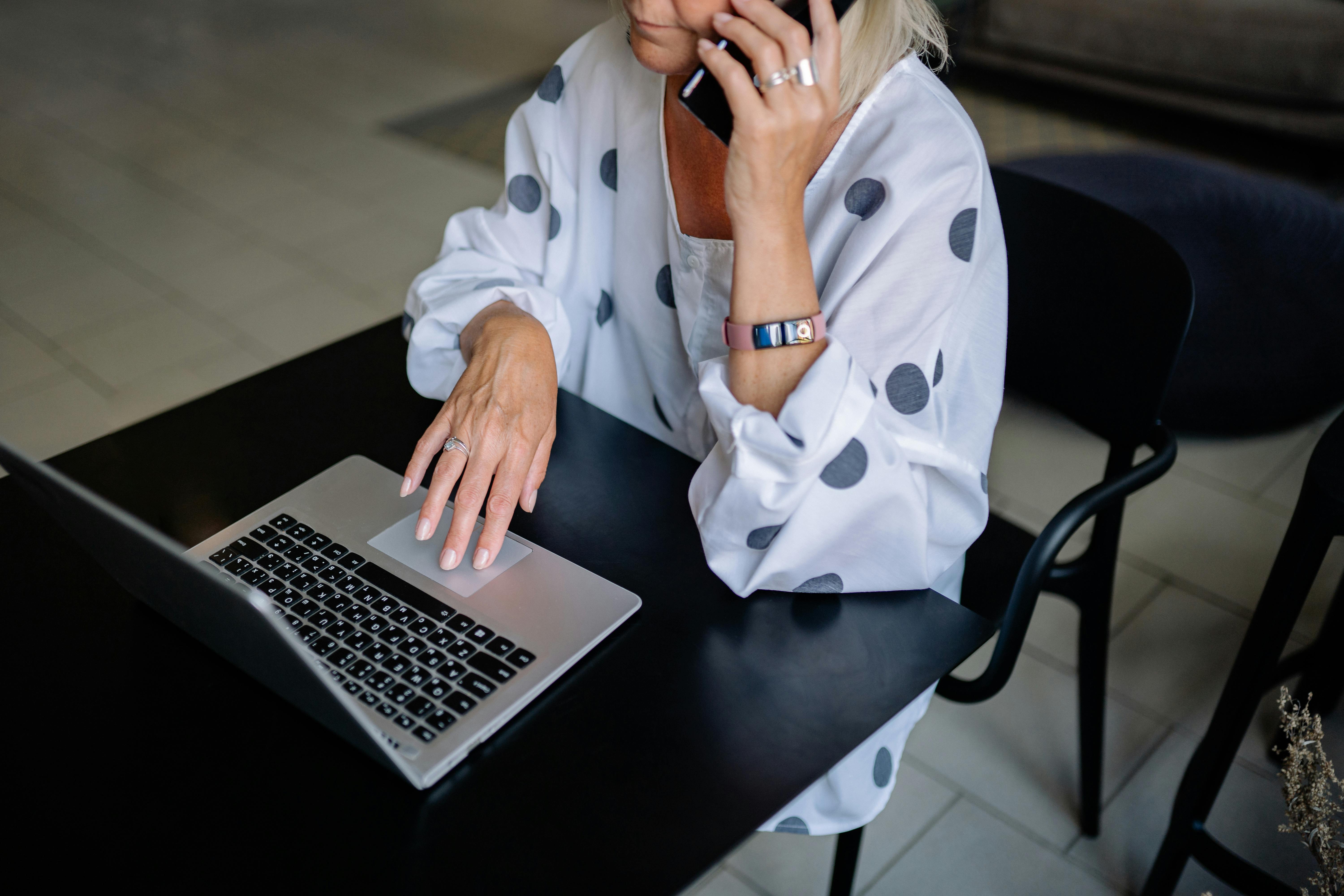 Woman Using a Laptop While one the Phone · Free Stock Photo