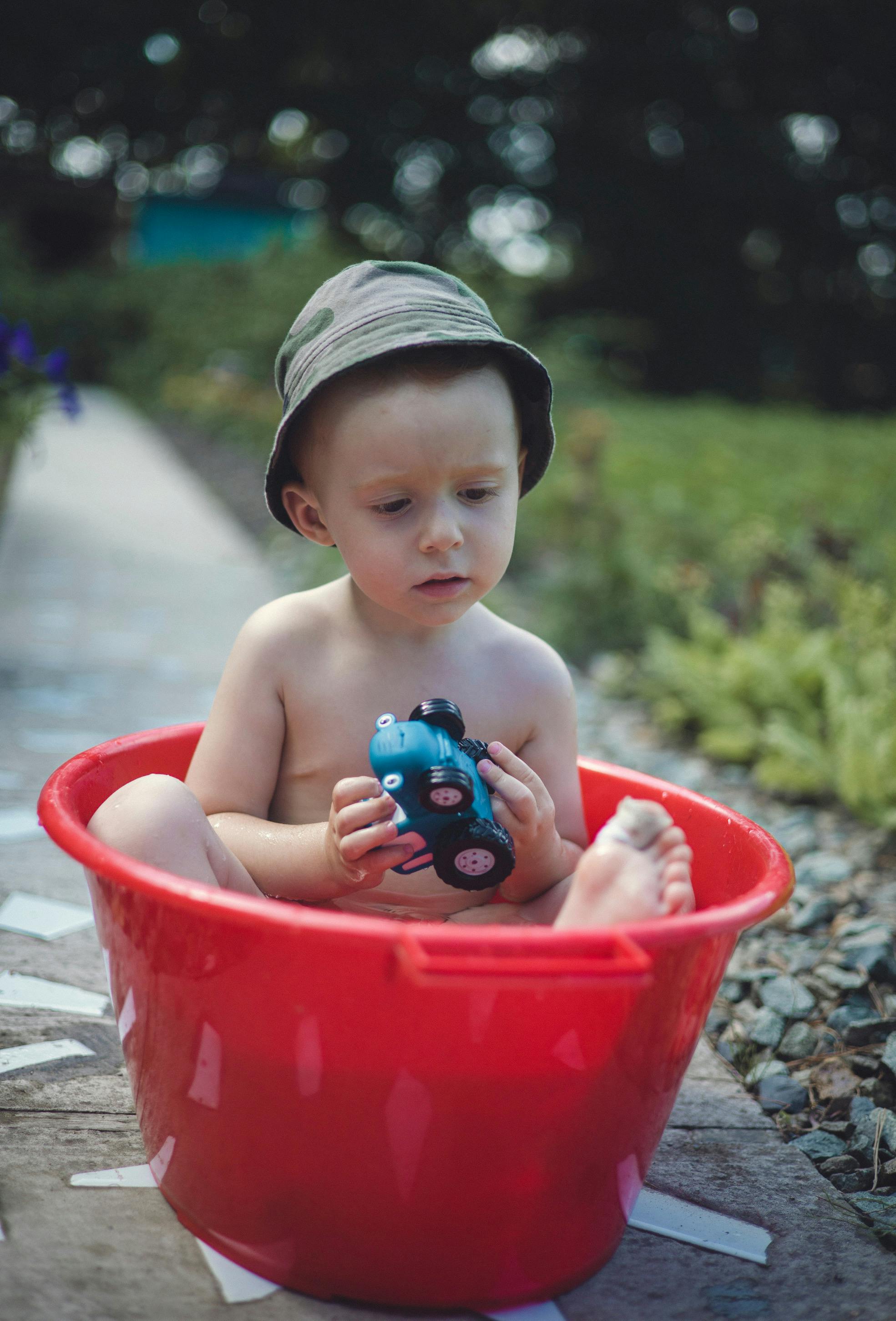 Little Boy in a Red Plastic Bucket · Free Stock Photo