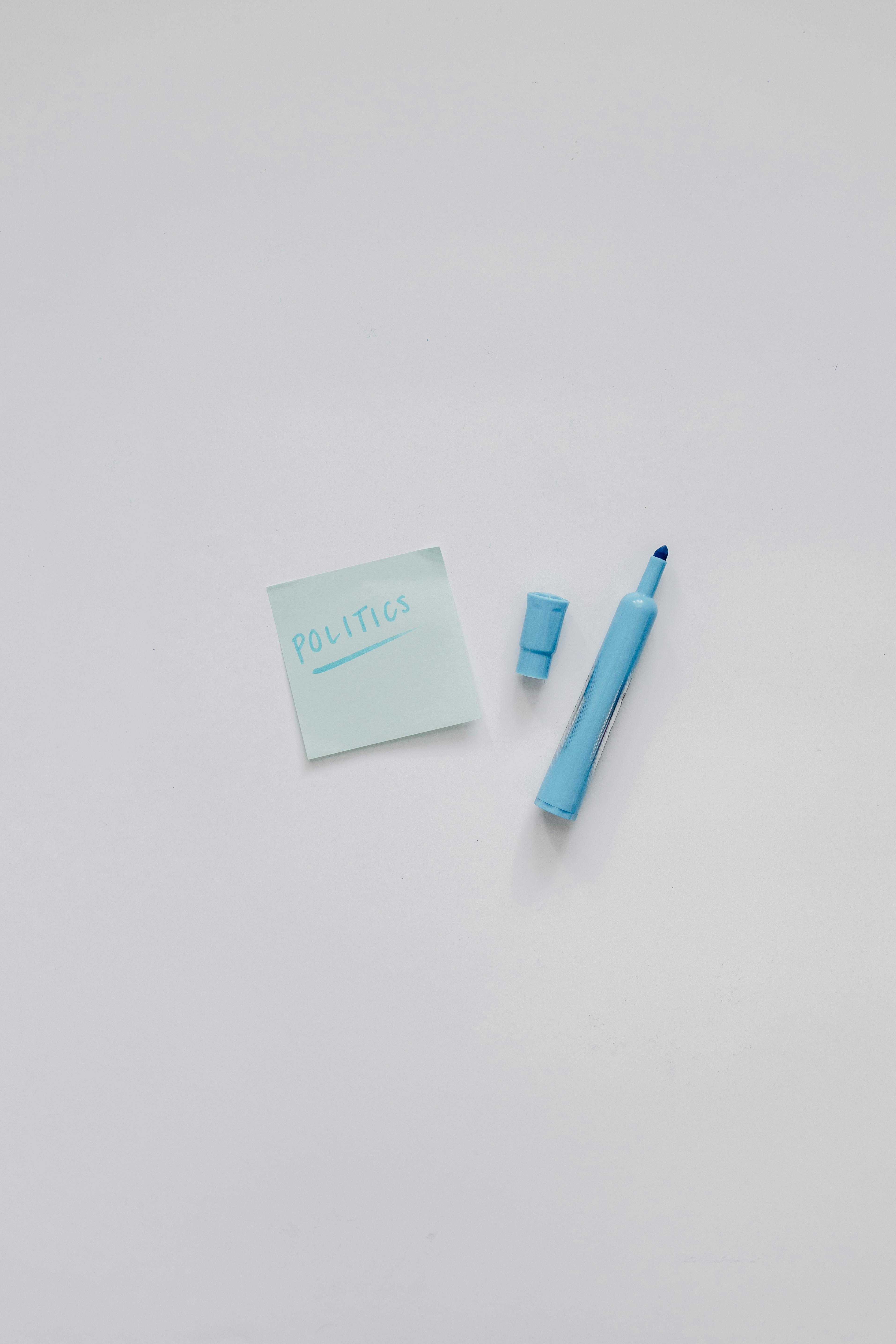 A Sticky Note and a Blue Pen on a White Background · Free Stock Photo
