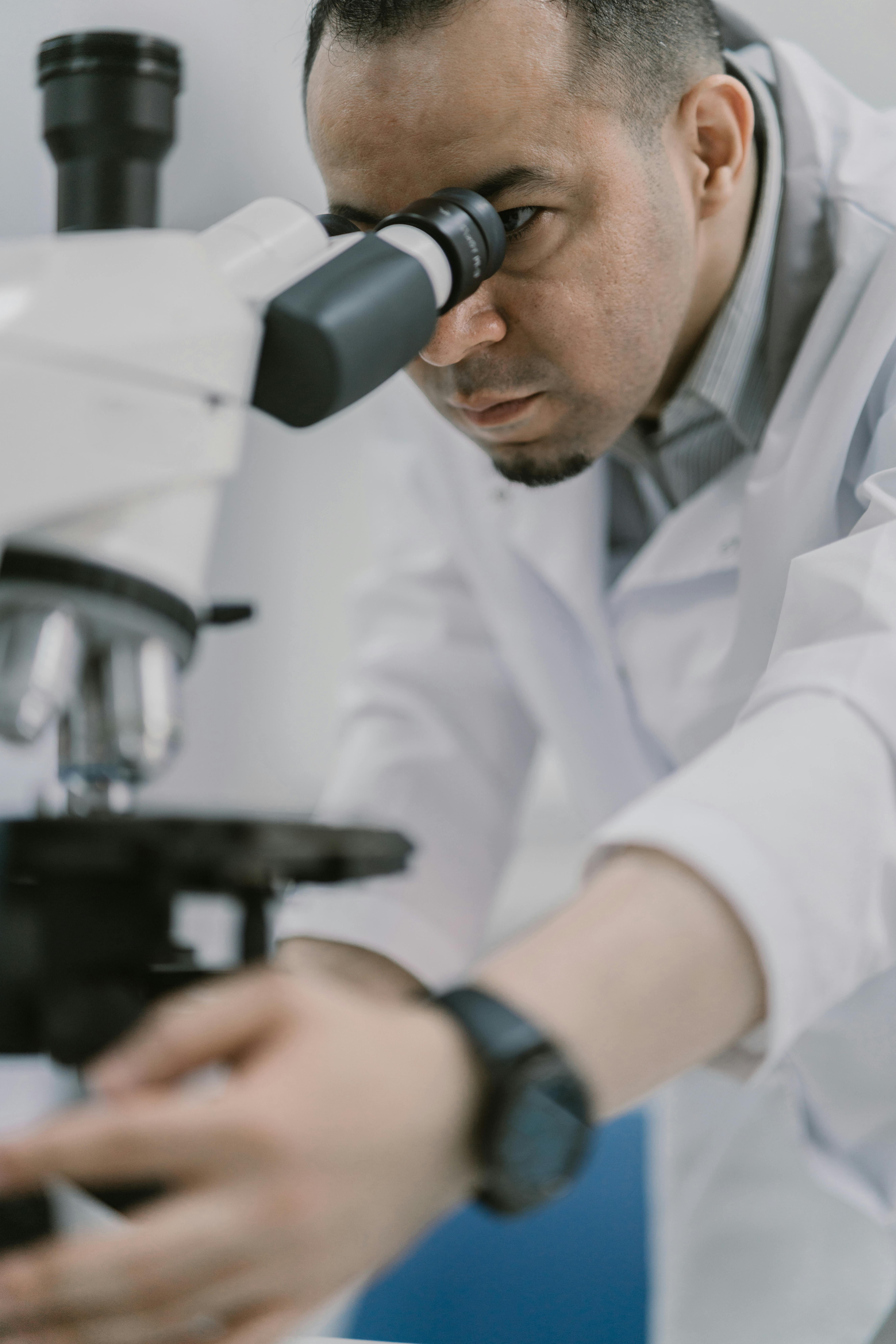 Man in Laboratory Gown Looking into Microscope · Free Stock Photo