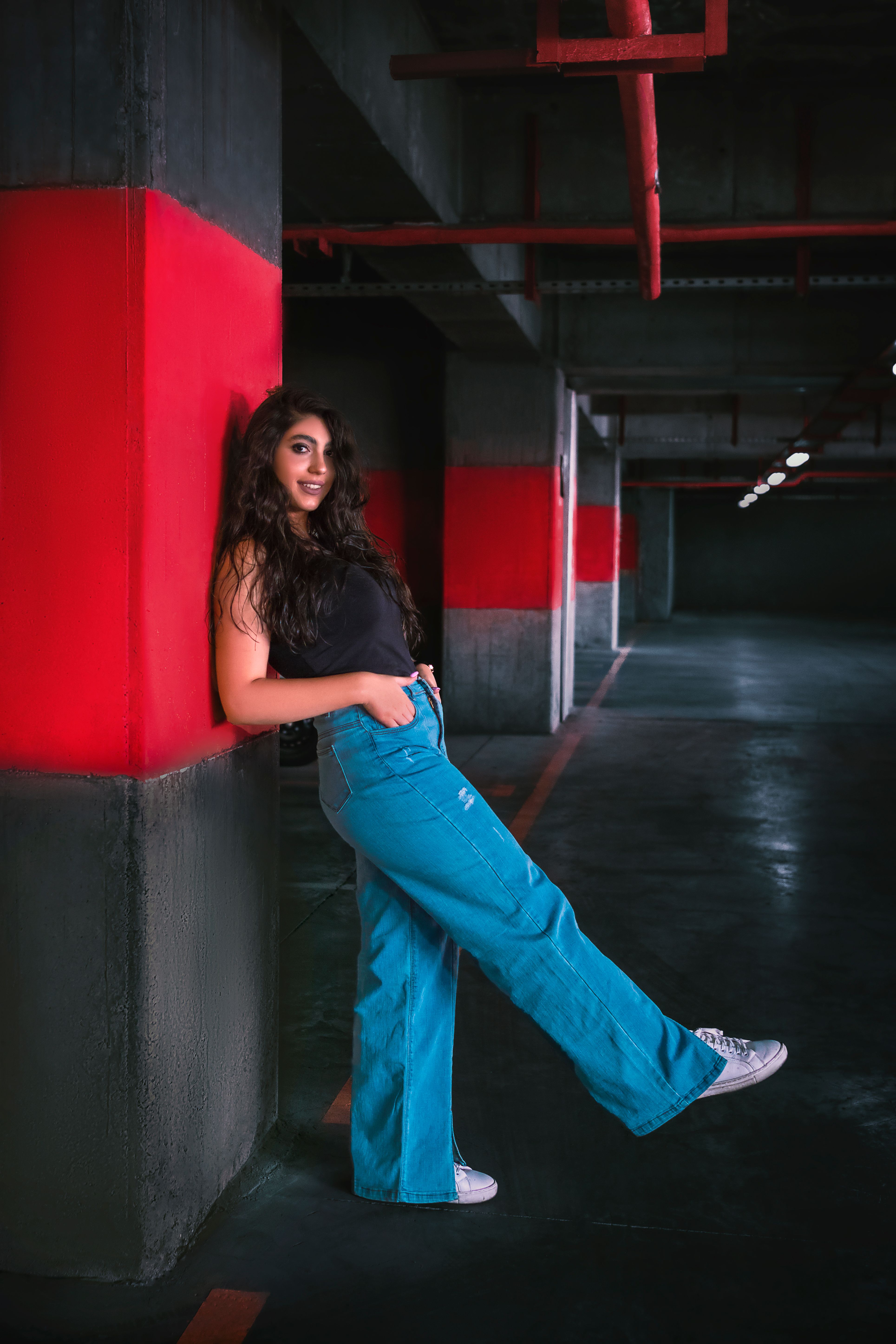 Woman in Denim Jeans Leaning on a Red Surface · Free Stock Photo