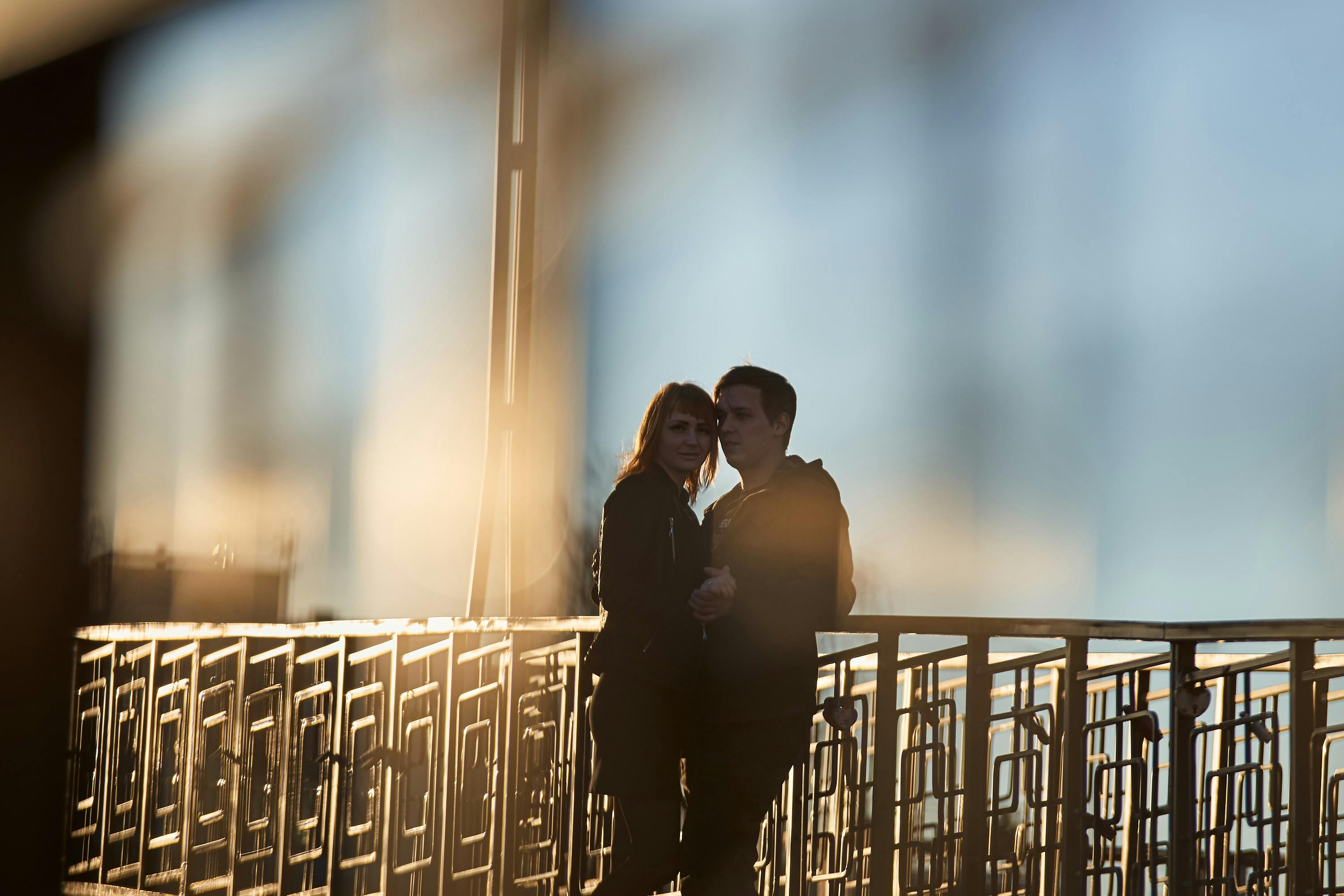 A Couple Standing Close Together by a Metal Railing · Free Stock Photo