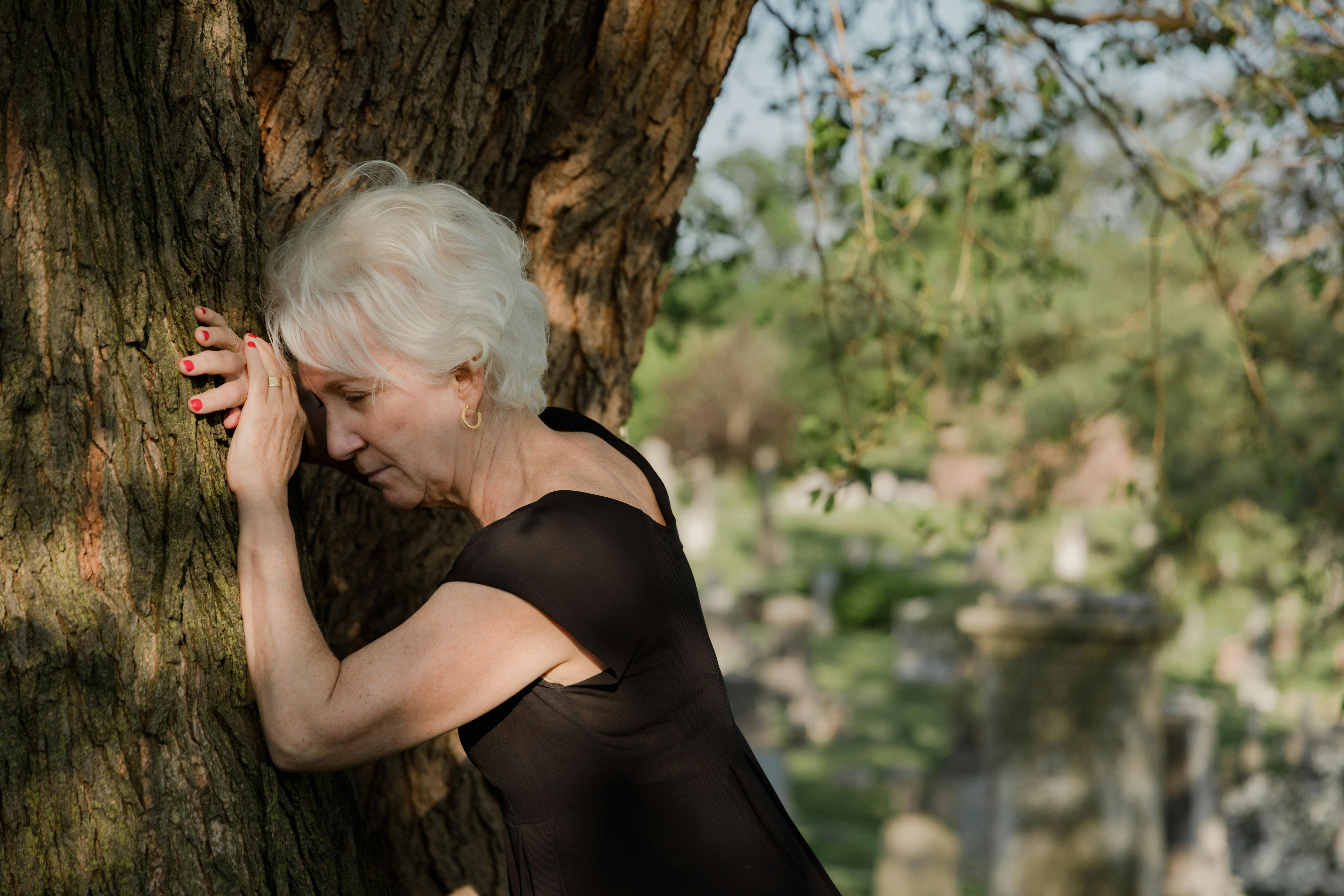 An Elderly Woman Posing in front of a Tree · Free Stock Photo
