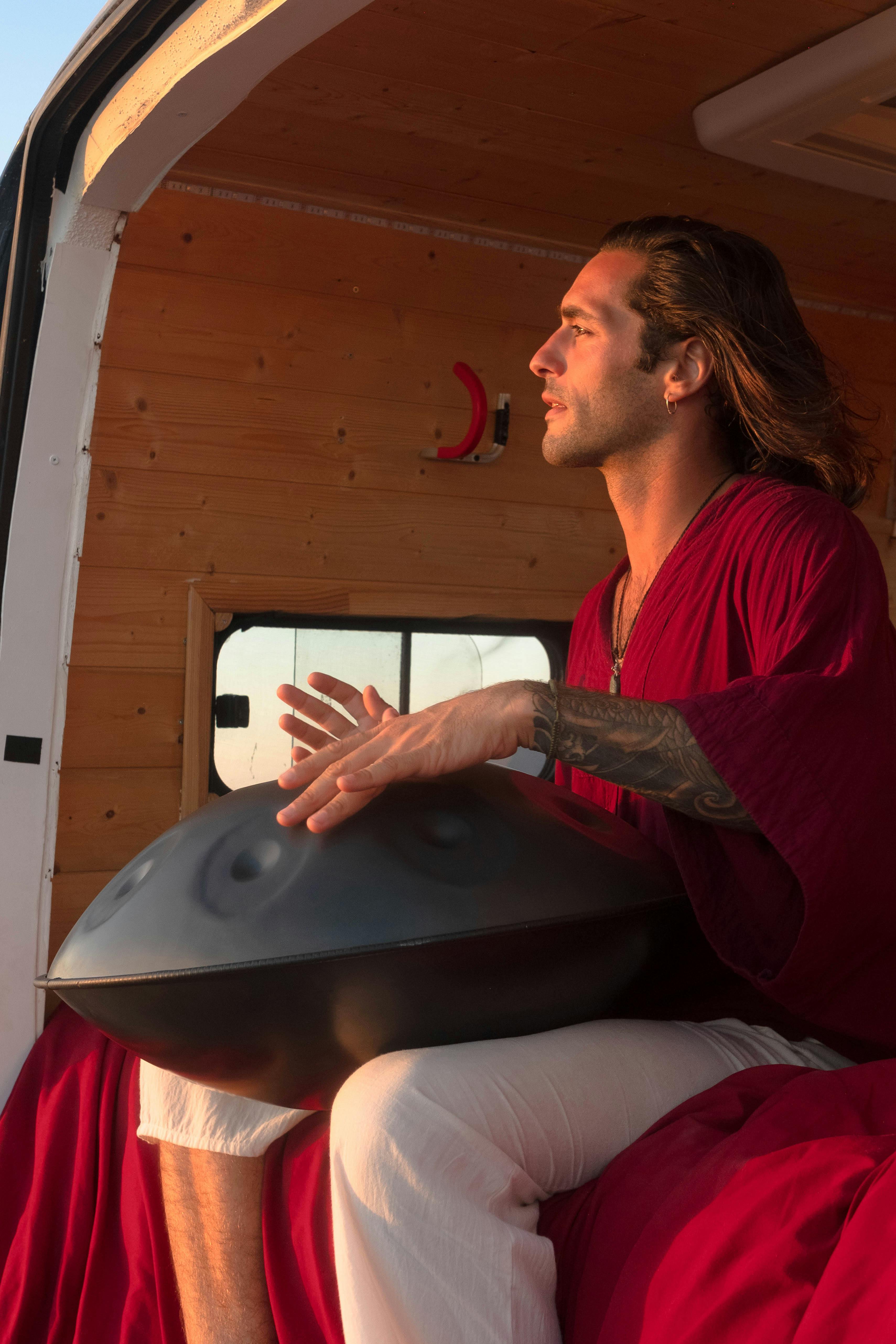 A Man Playing the Steelpan while Sitting · Free Stock Photo