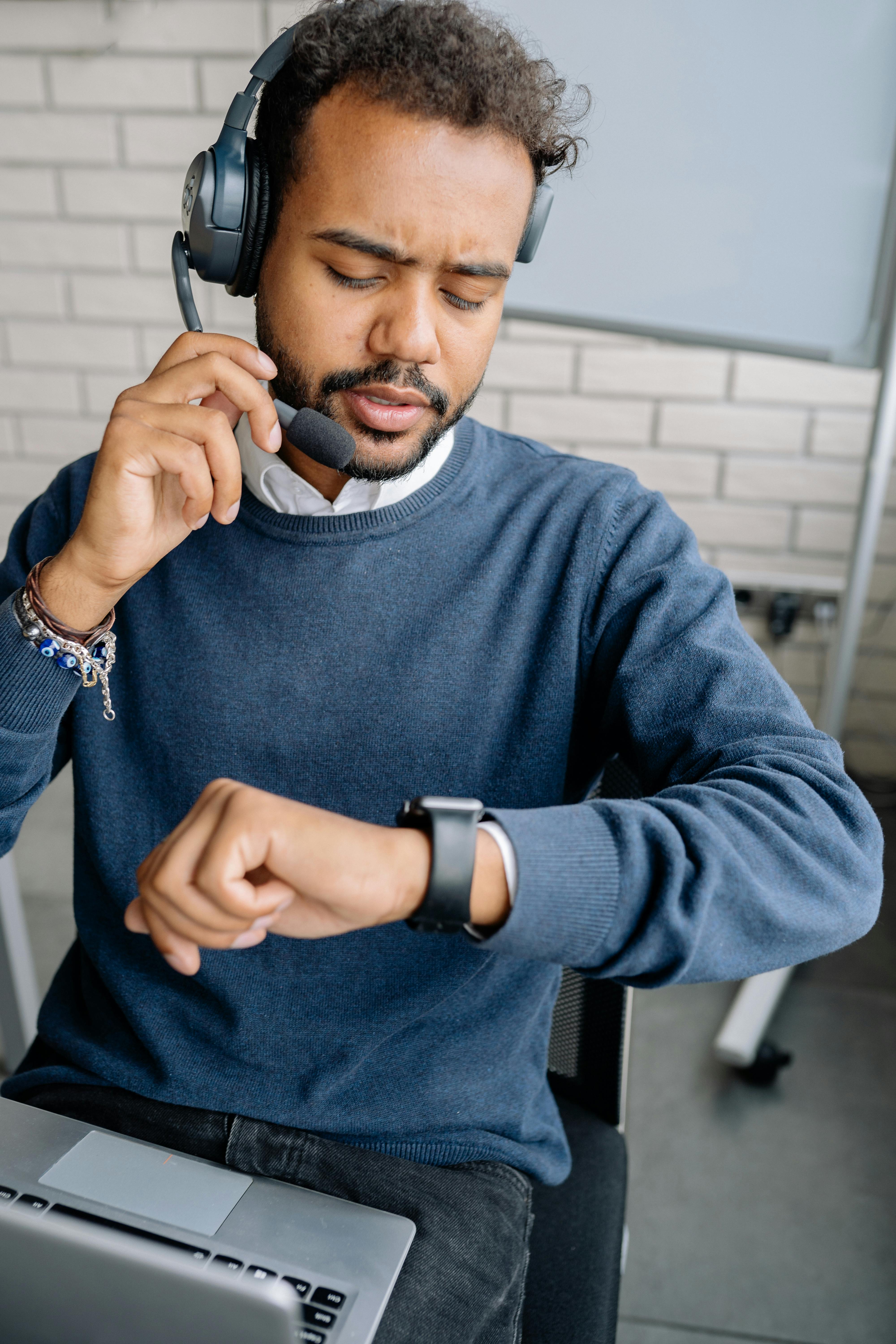 Man Holding his Headset while Looking at his Watch · Free Stock Photo