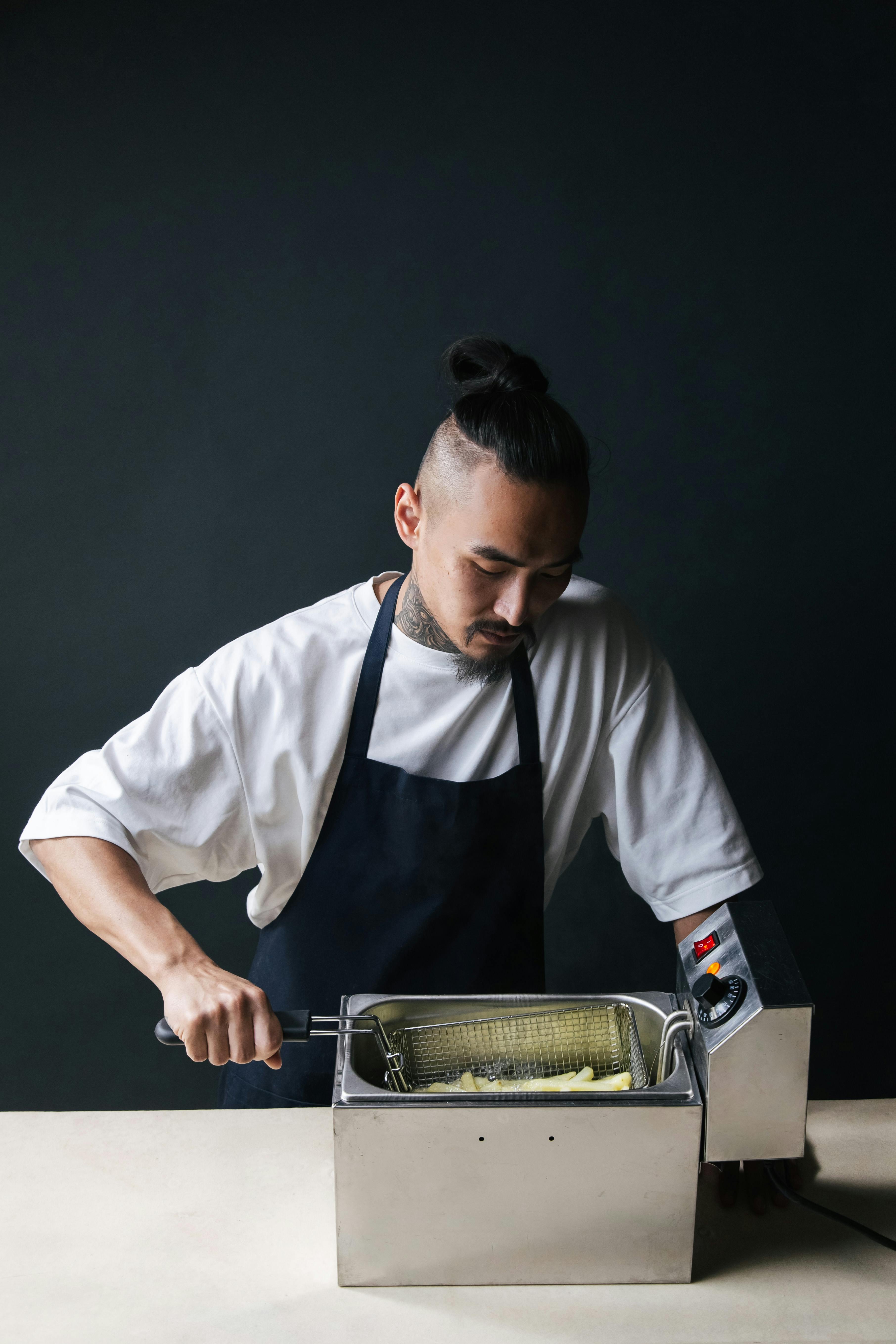 Photo of a Man in a White Shirt Frying French Fries · Free Stock Photo