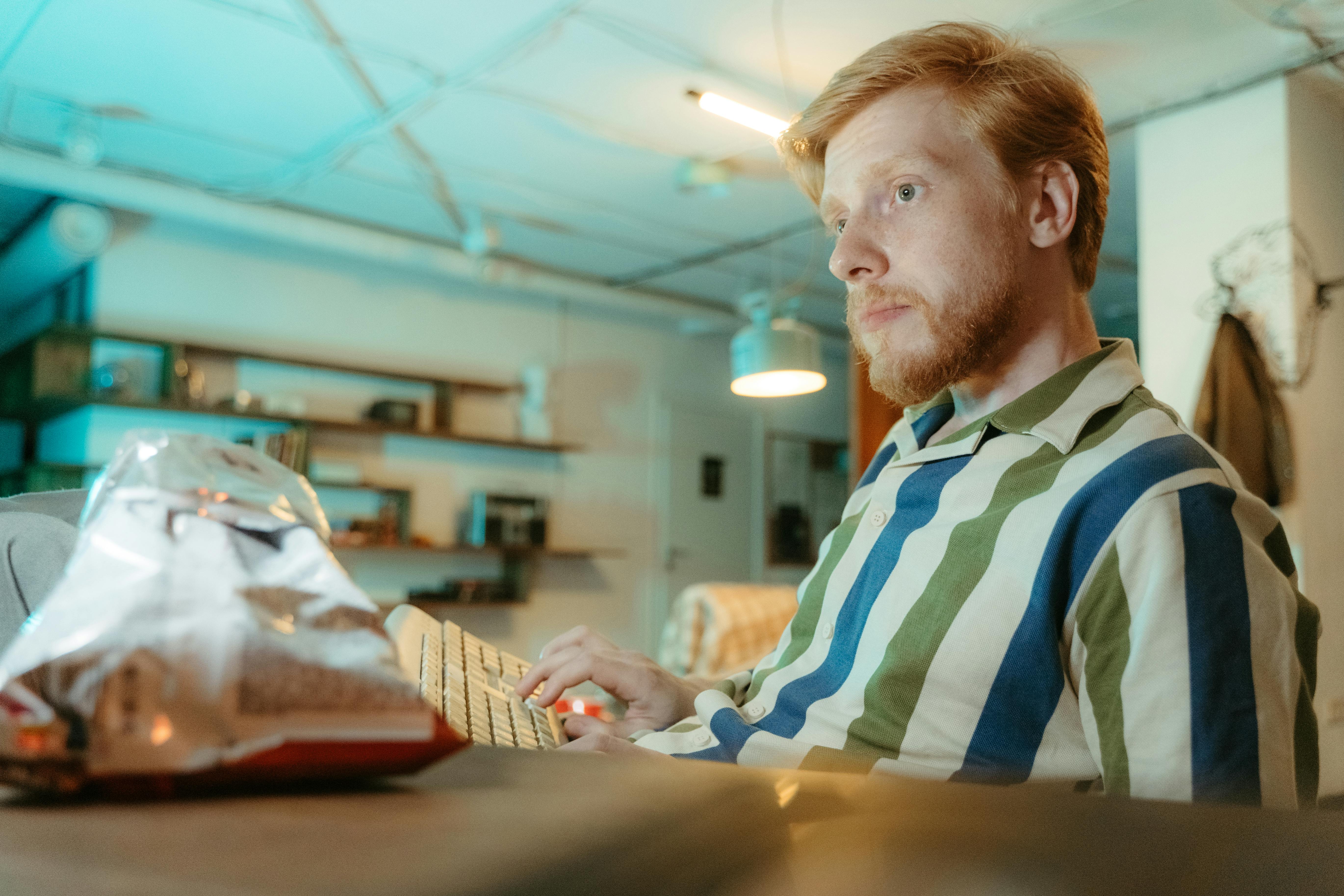 Man in Striped Using a Keyboard · Free Stock Photo