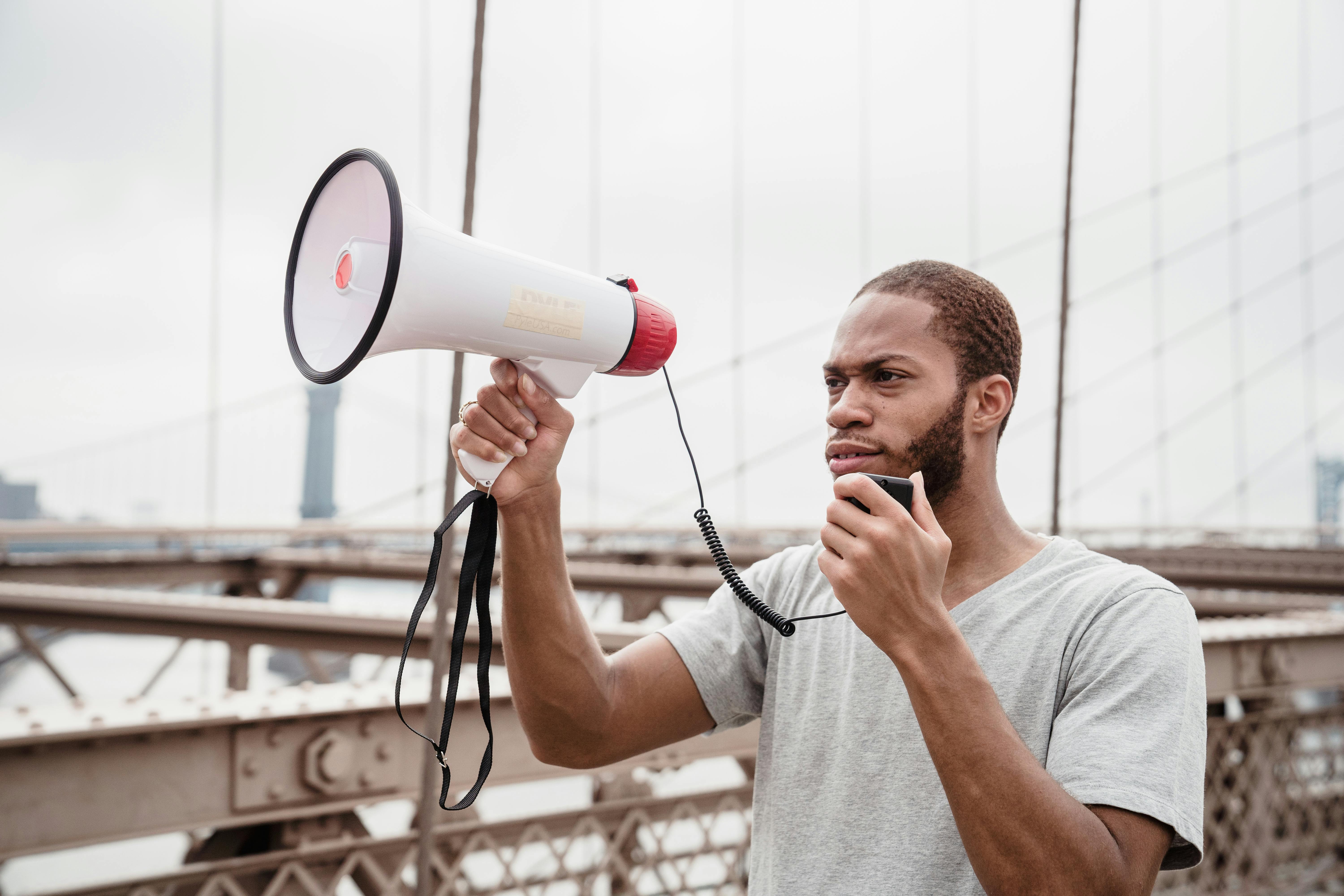 Protester in White Crew Neck holding Megaphone · Free Stock Photo