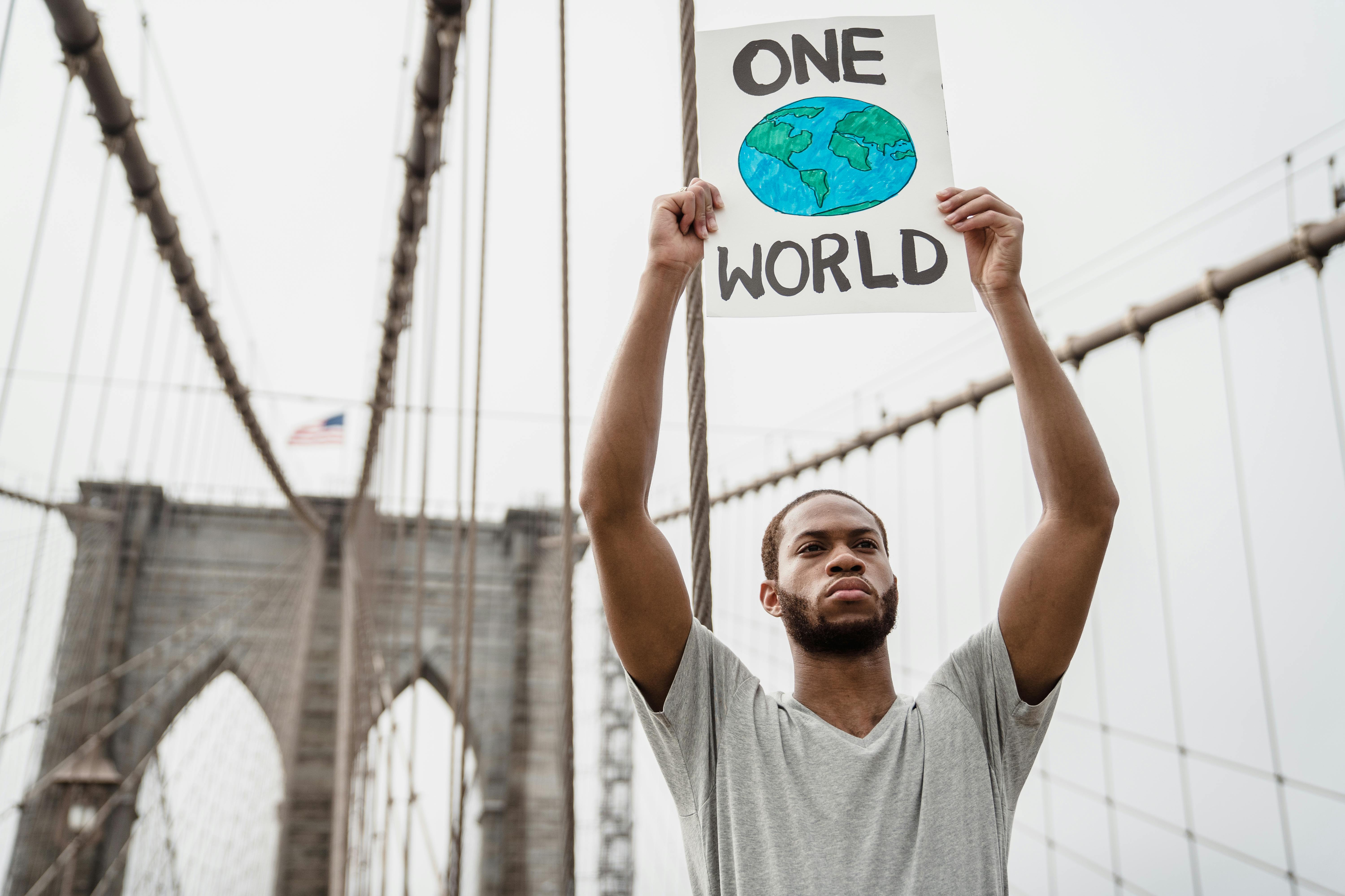 Man with Poster Protesting on Bridge · Free Stock Photo