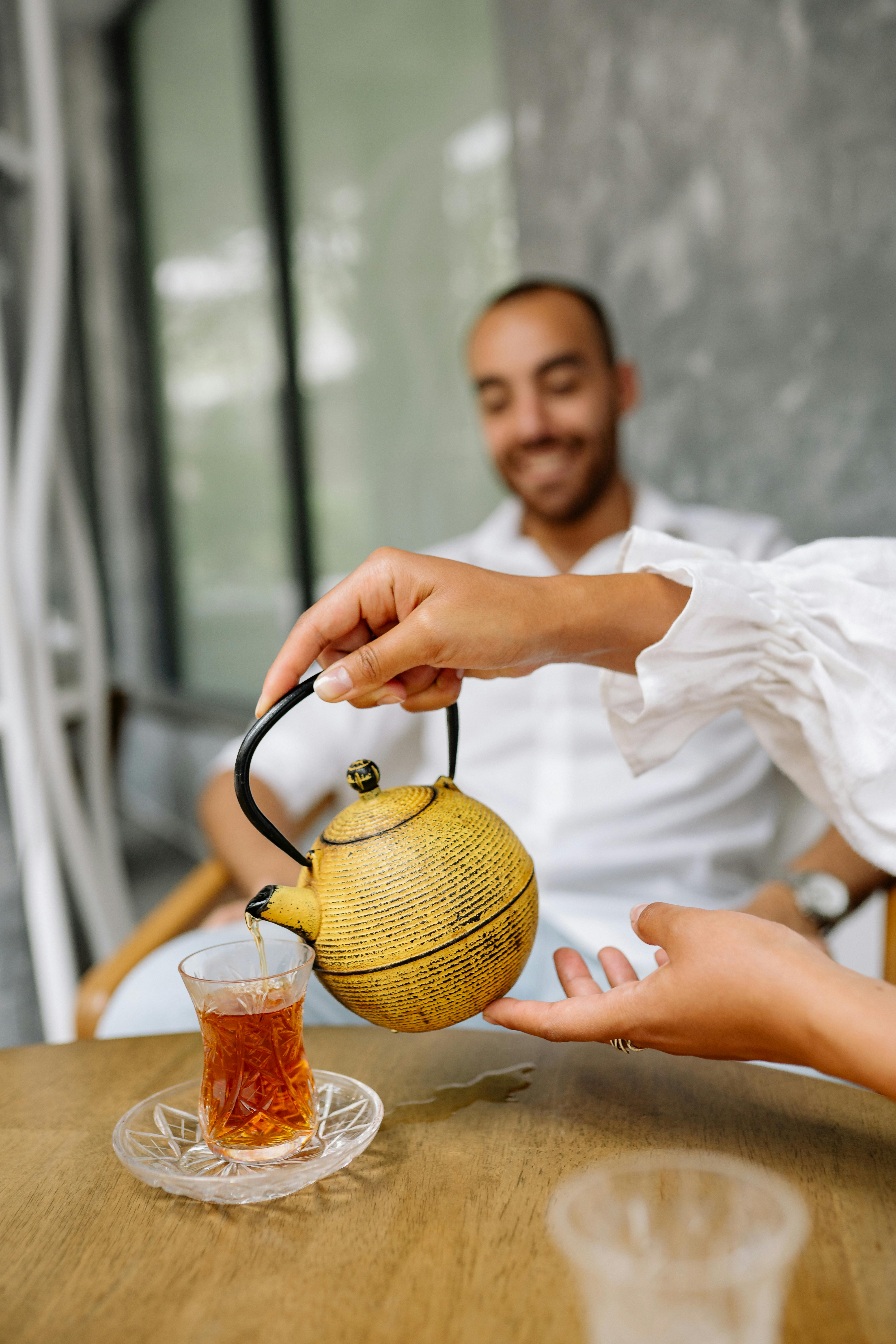 A Person Pouring a Tea in a Tea Cup · Free Stock Photo