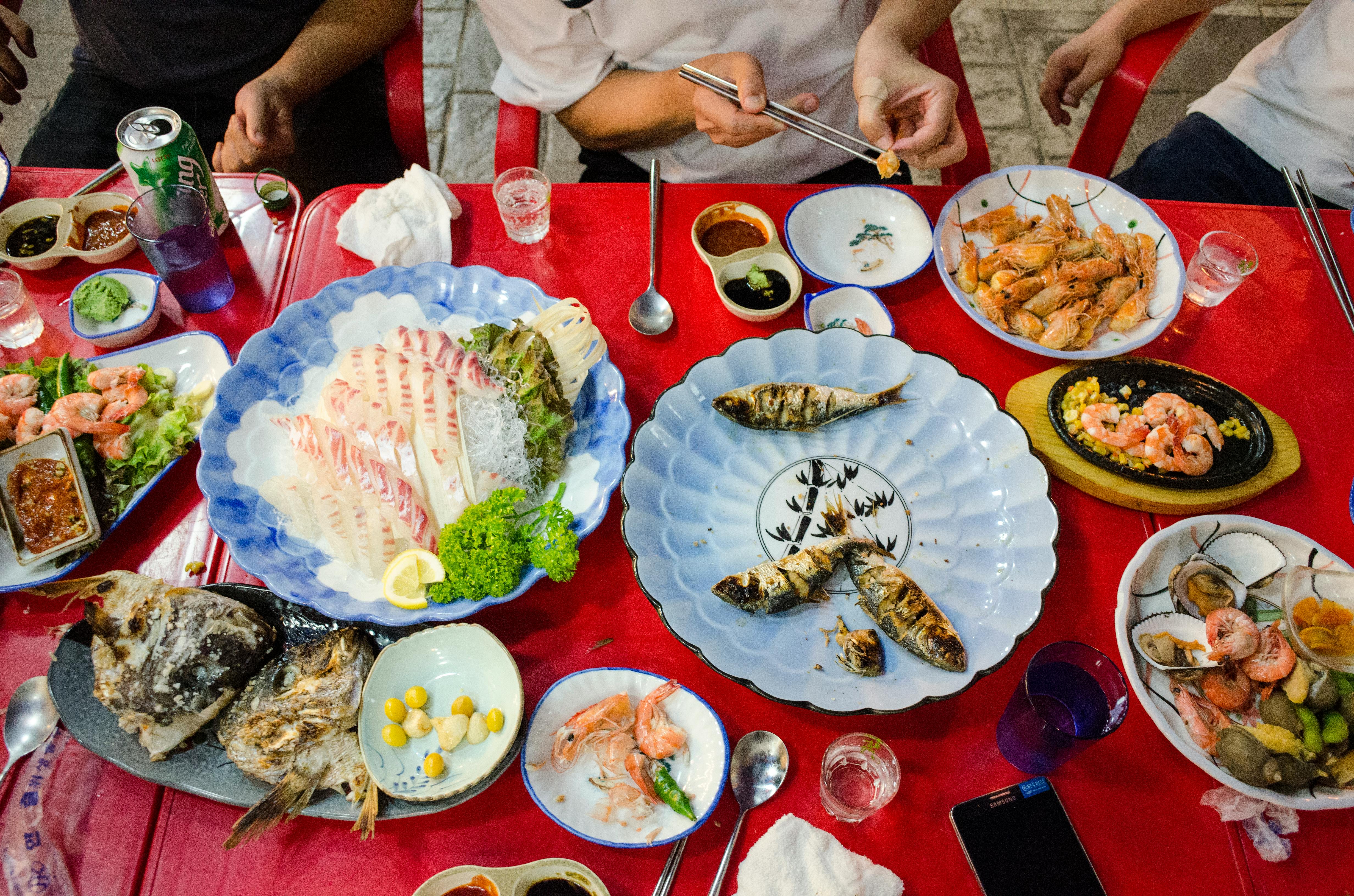 High-Angle Shot of People Eating Sea Food on Red Table · Free Stock Photo