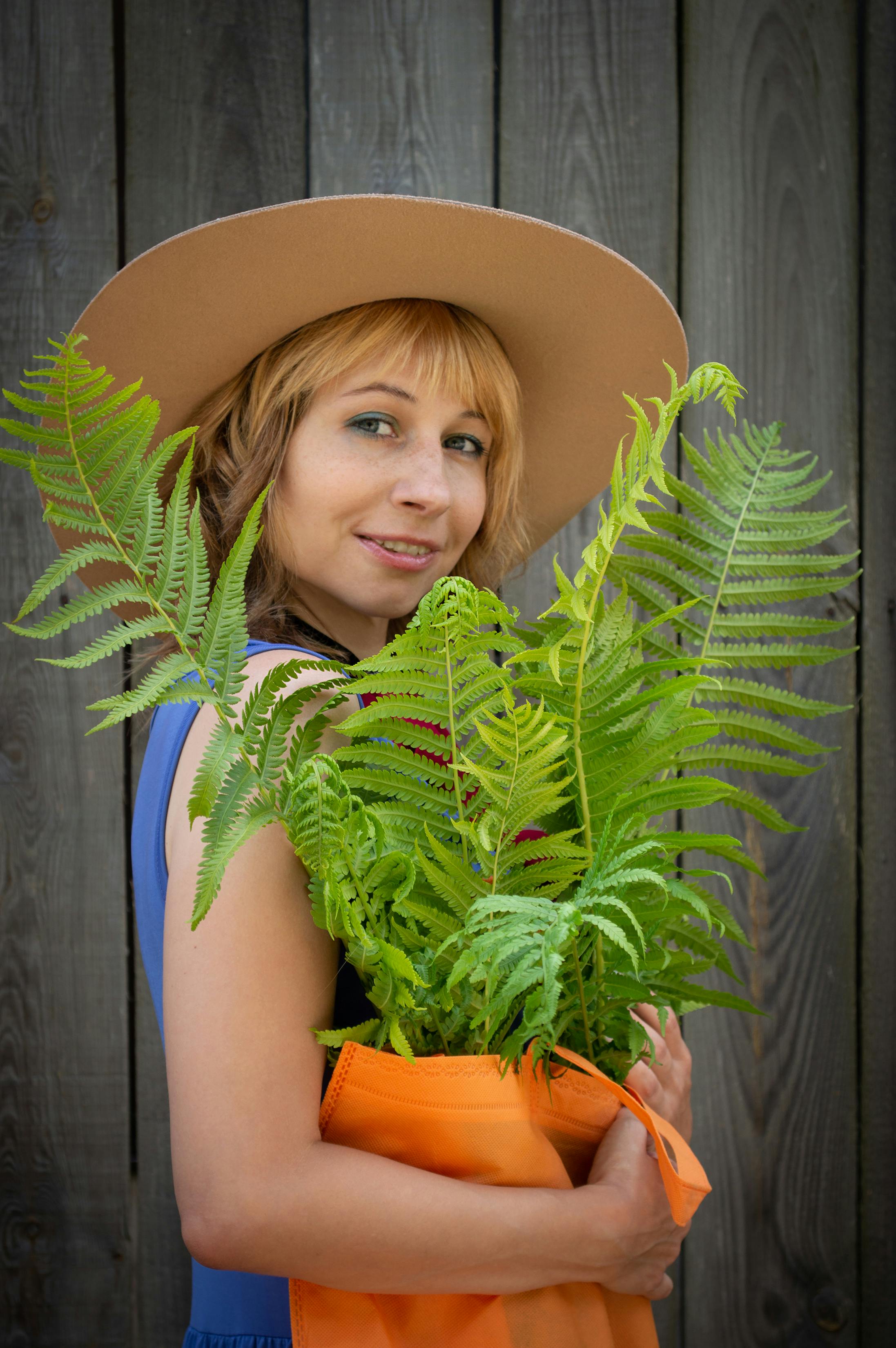 Woman in Blue Sleeveless Shirt Holding Green Leaves · Free Stock Photo