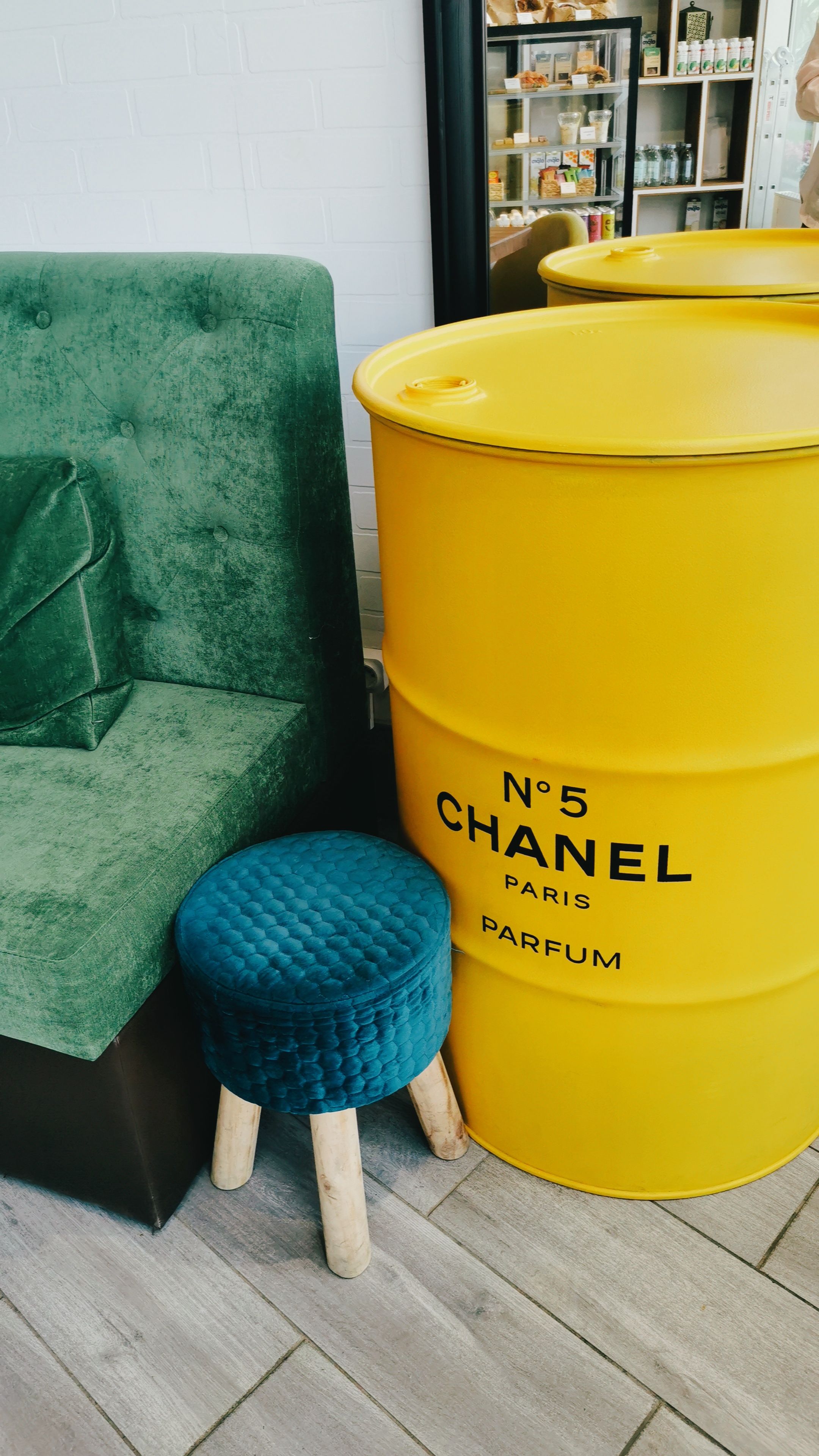 Chanel Perfume Drum Beside Green Sofa and Blue Stool · Free Stock Photo