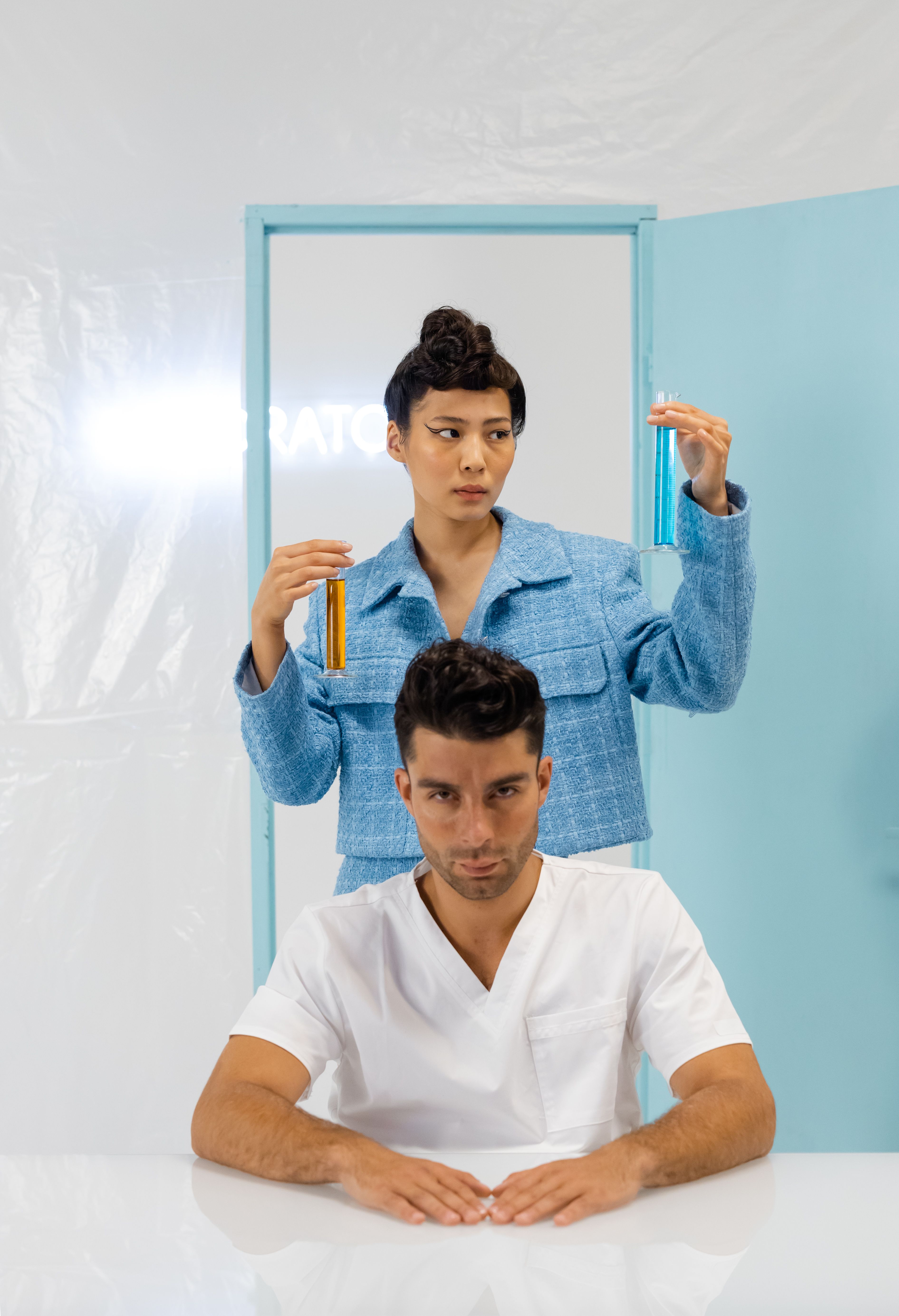 Woman Holding Graduated Cylinders Behind a Man · Free Stock Photo