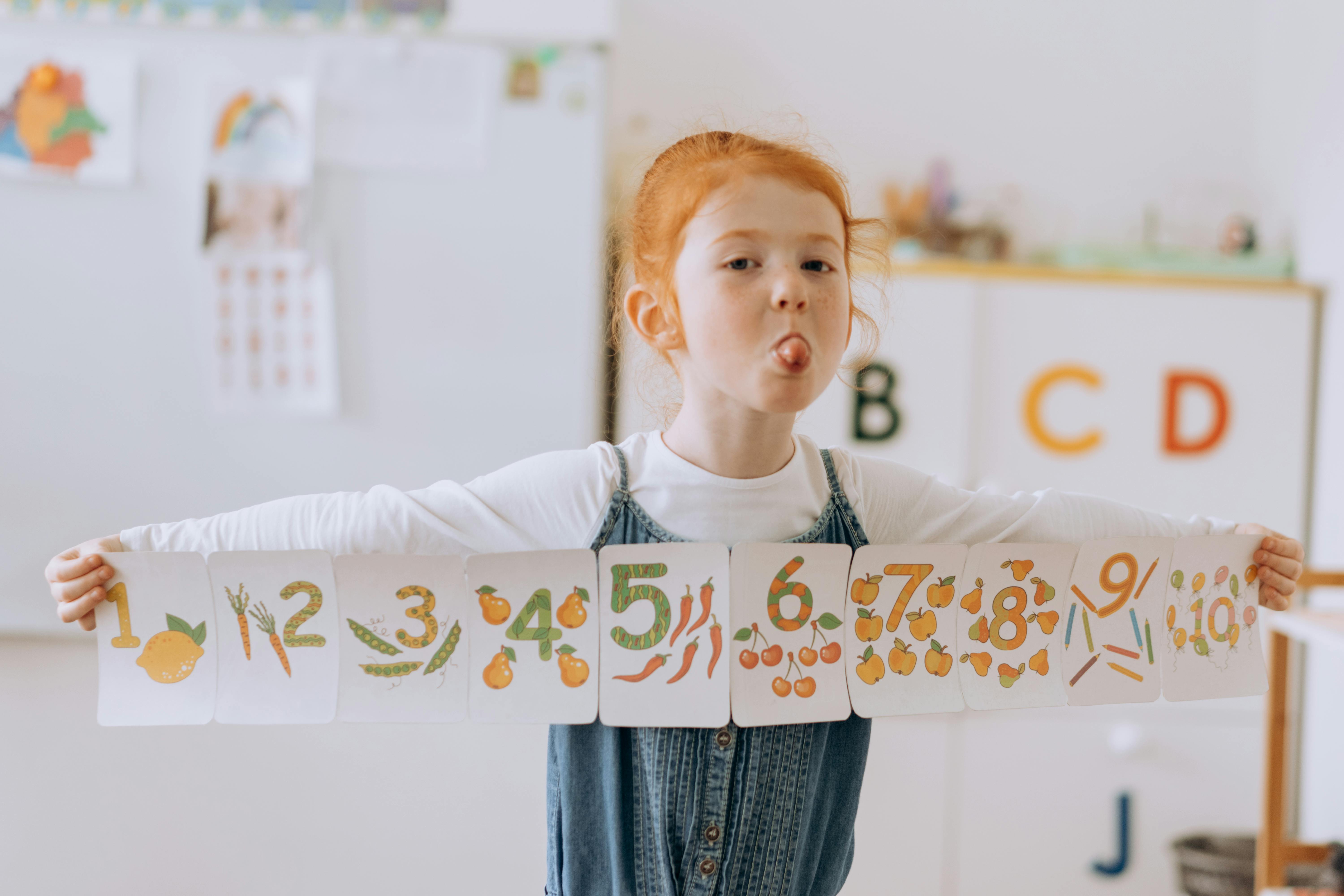 Little Girl Holding Numbers Drawings and Sticking Out Tongue · Free ...