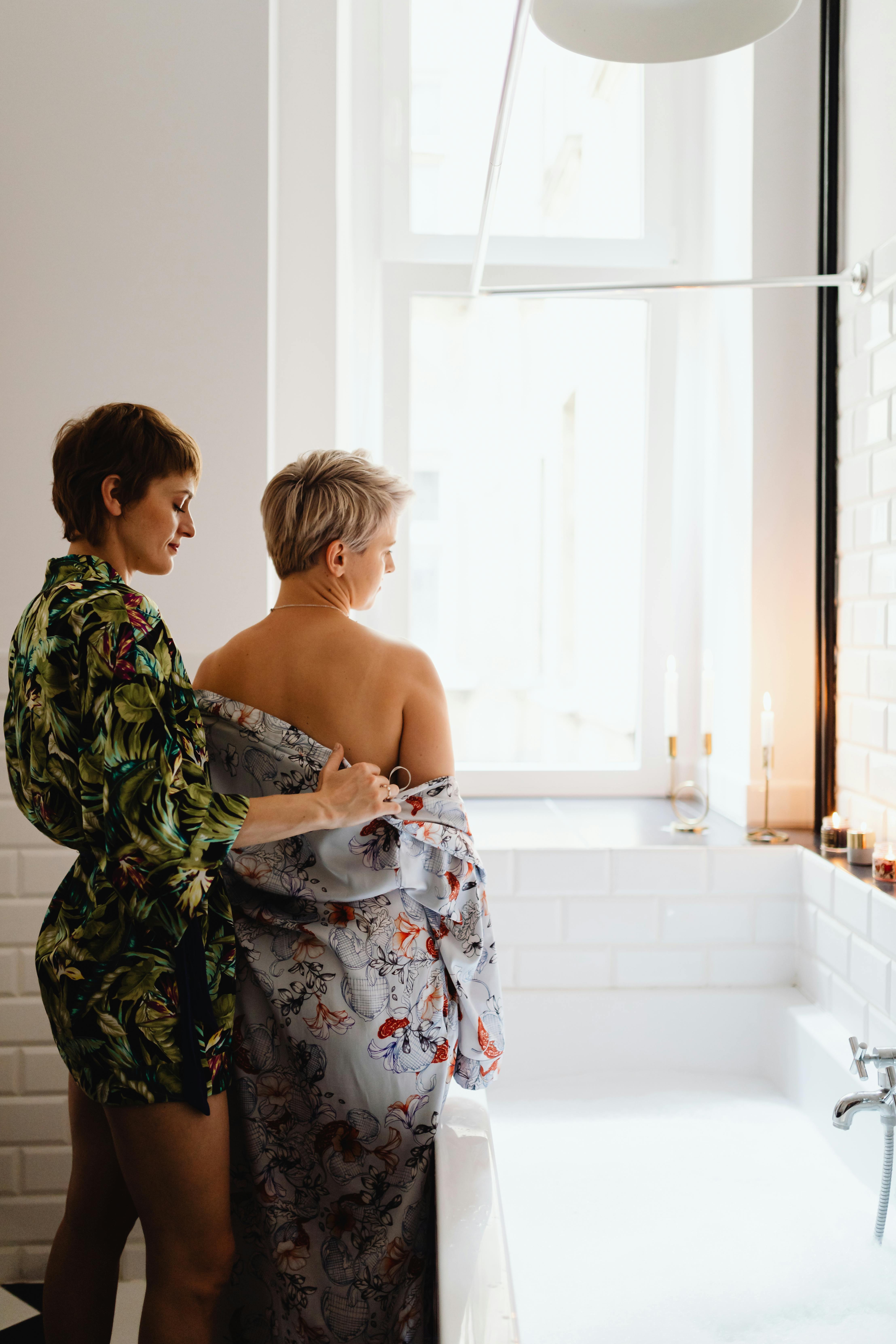 A Woman Removing another Woman's Robe · Free Stock Photo