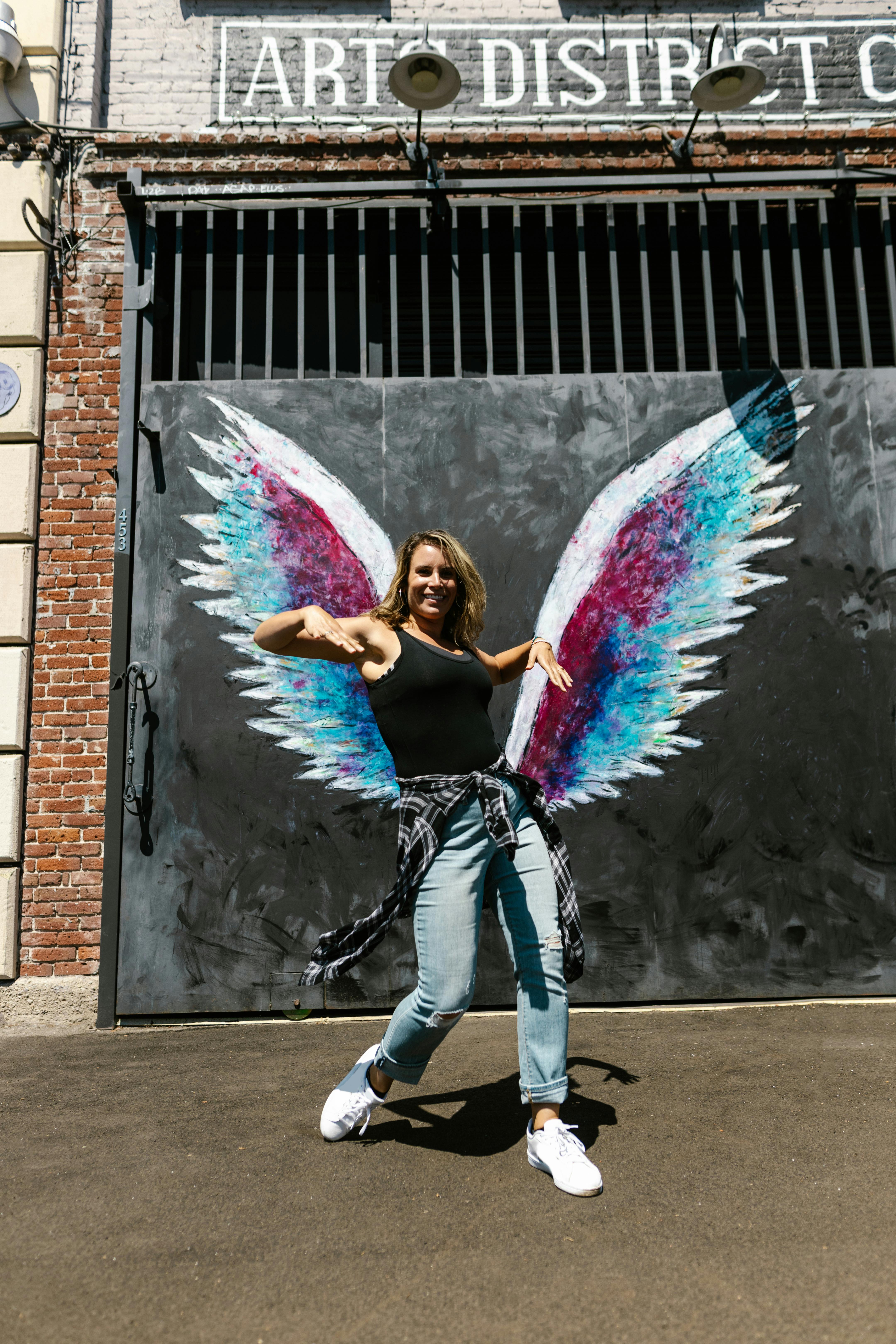 Photo of a Woman Dancing Near a Wall with Graffiti · Free Stock Photo