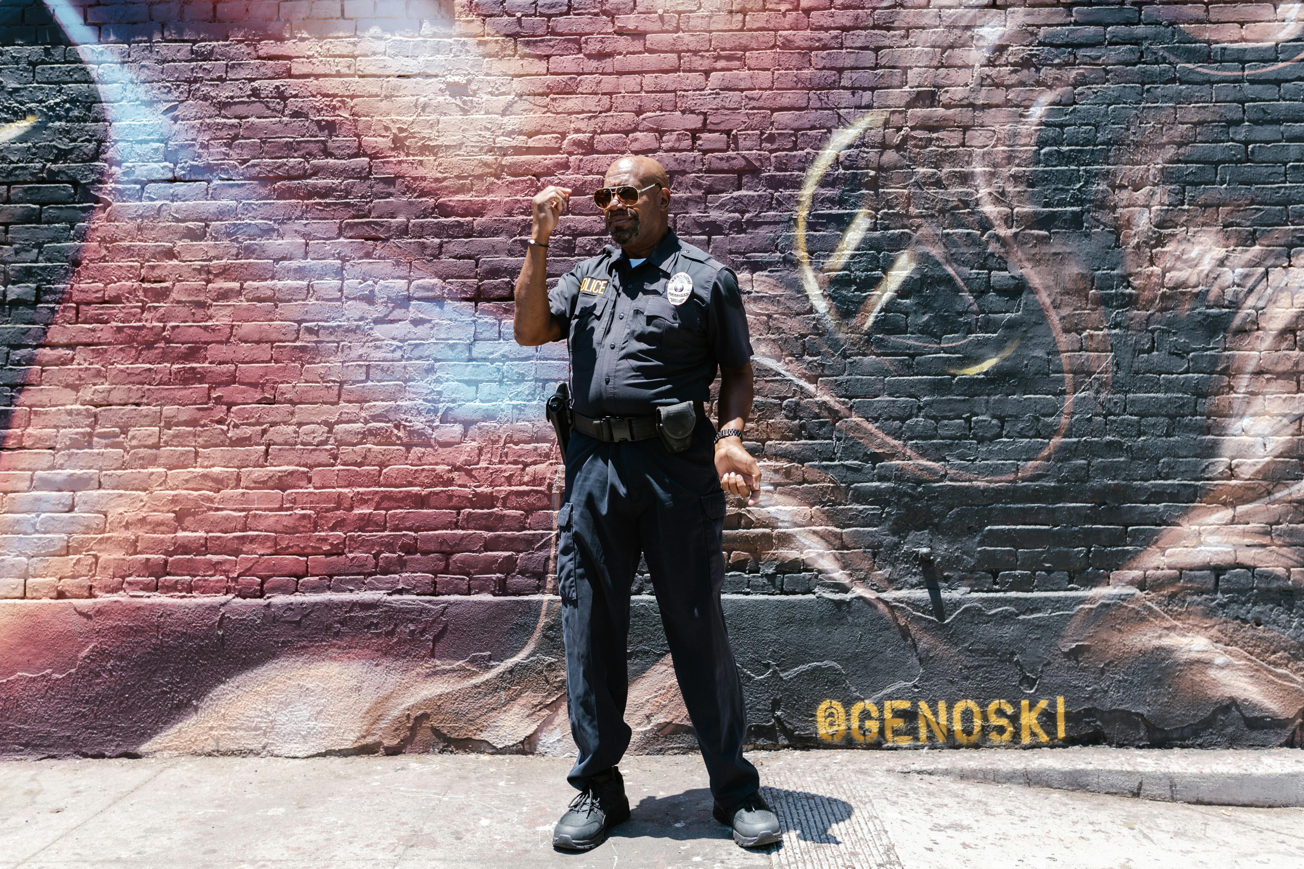 A Policeman Dancing by a Brick Wall · Free Stock Photo