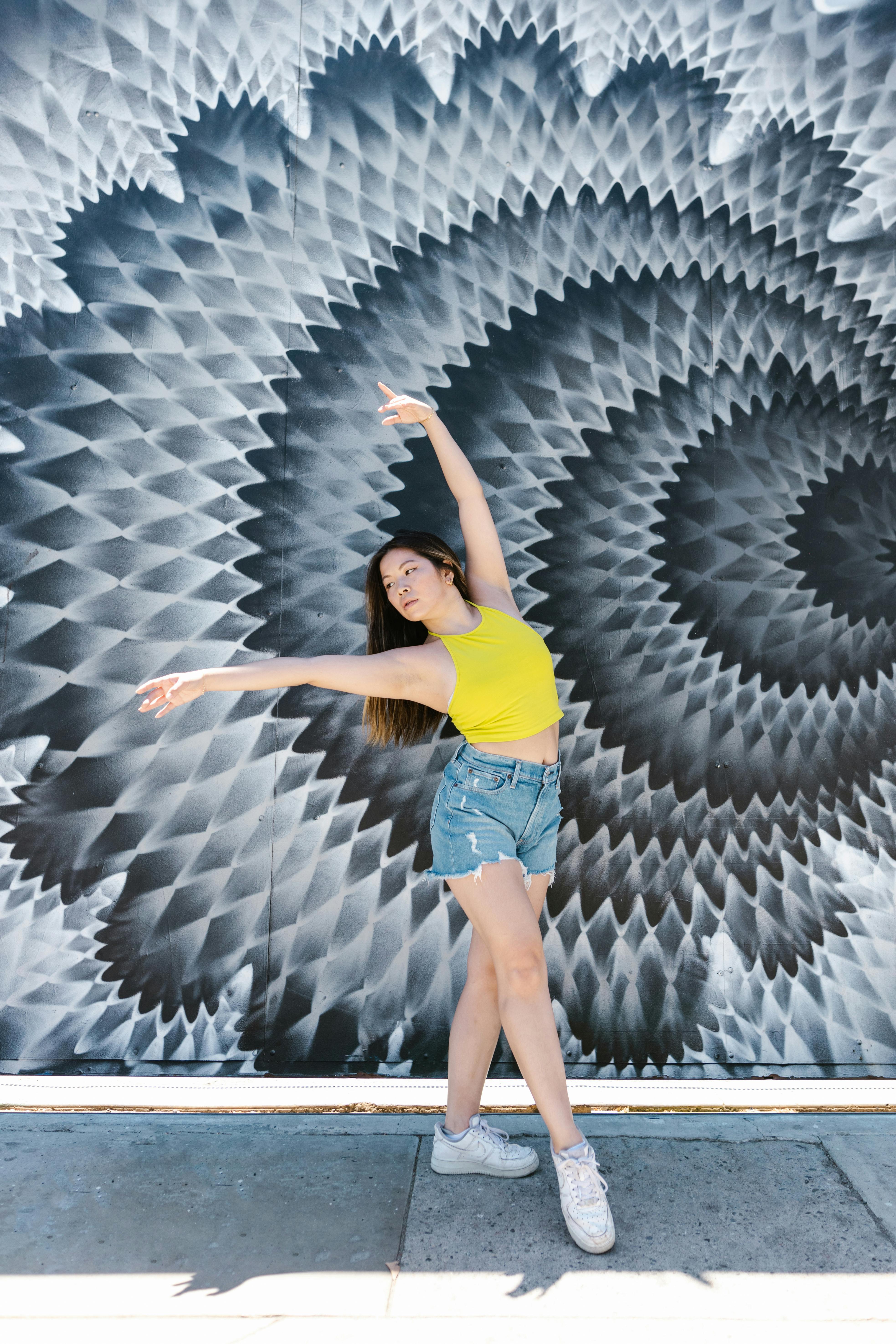 Woman in Yellow Tank Top and Blue Denim Shorts Dancing · Free Stock Photo