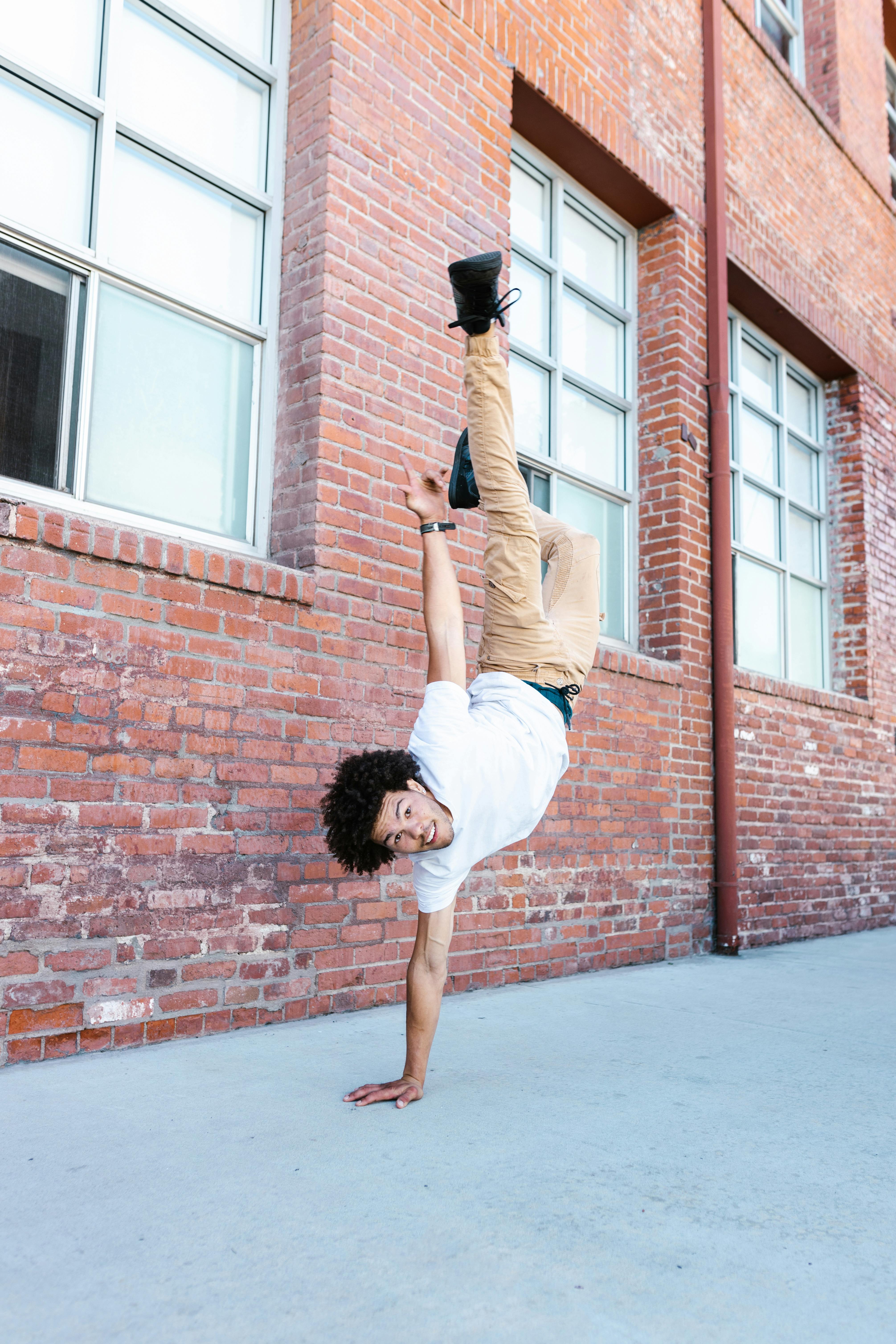 Man in White Shirt Doing a One Hand Stand · Free Stock Photo