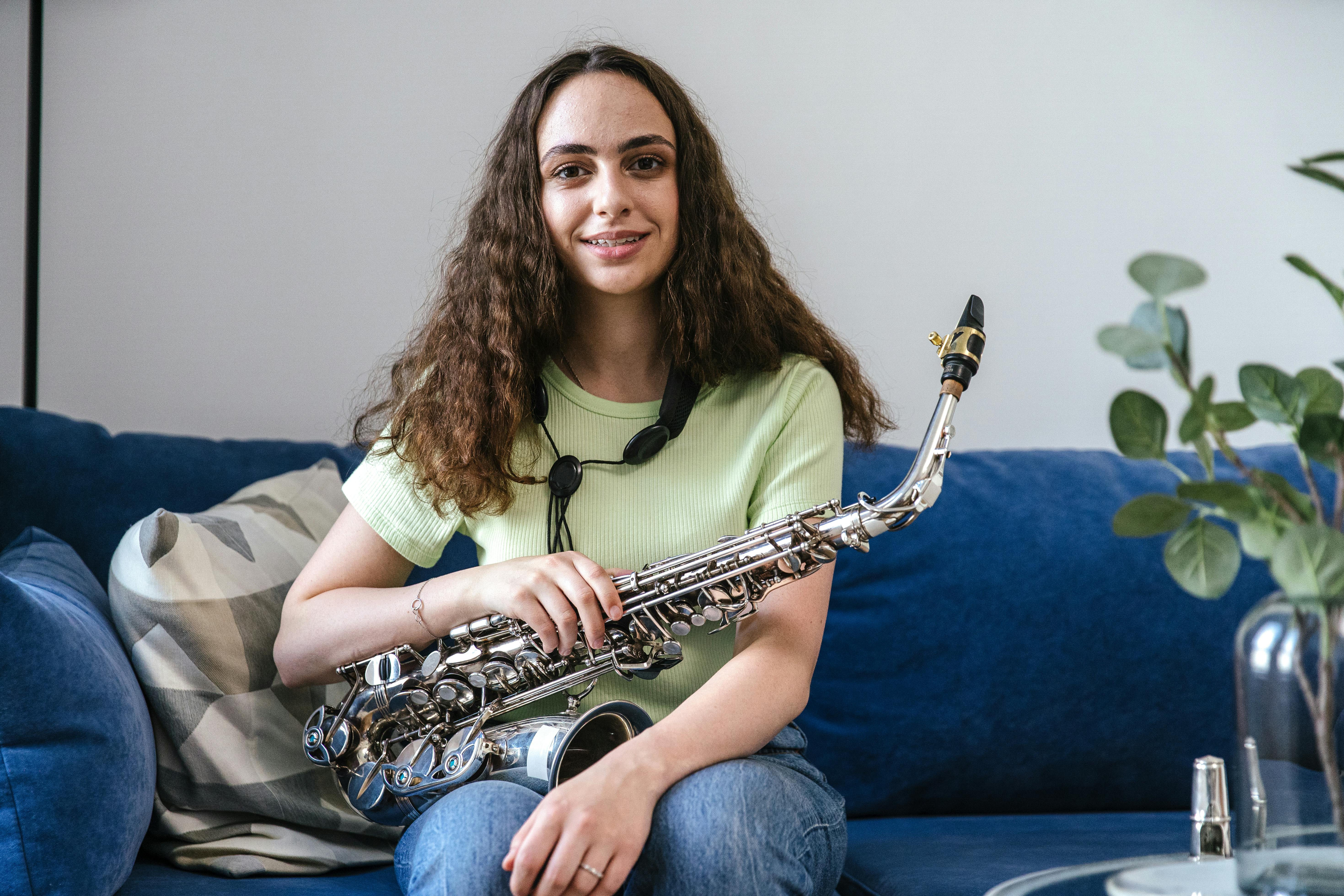 Woman Sitting on Blue Couch while Holding a Saxophone · Free Stock Photo