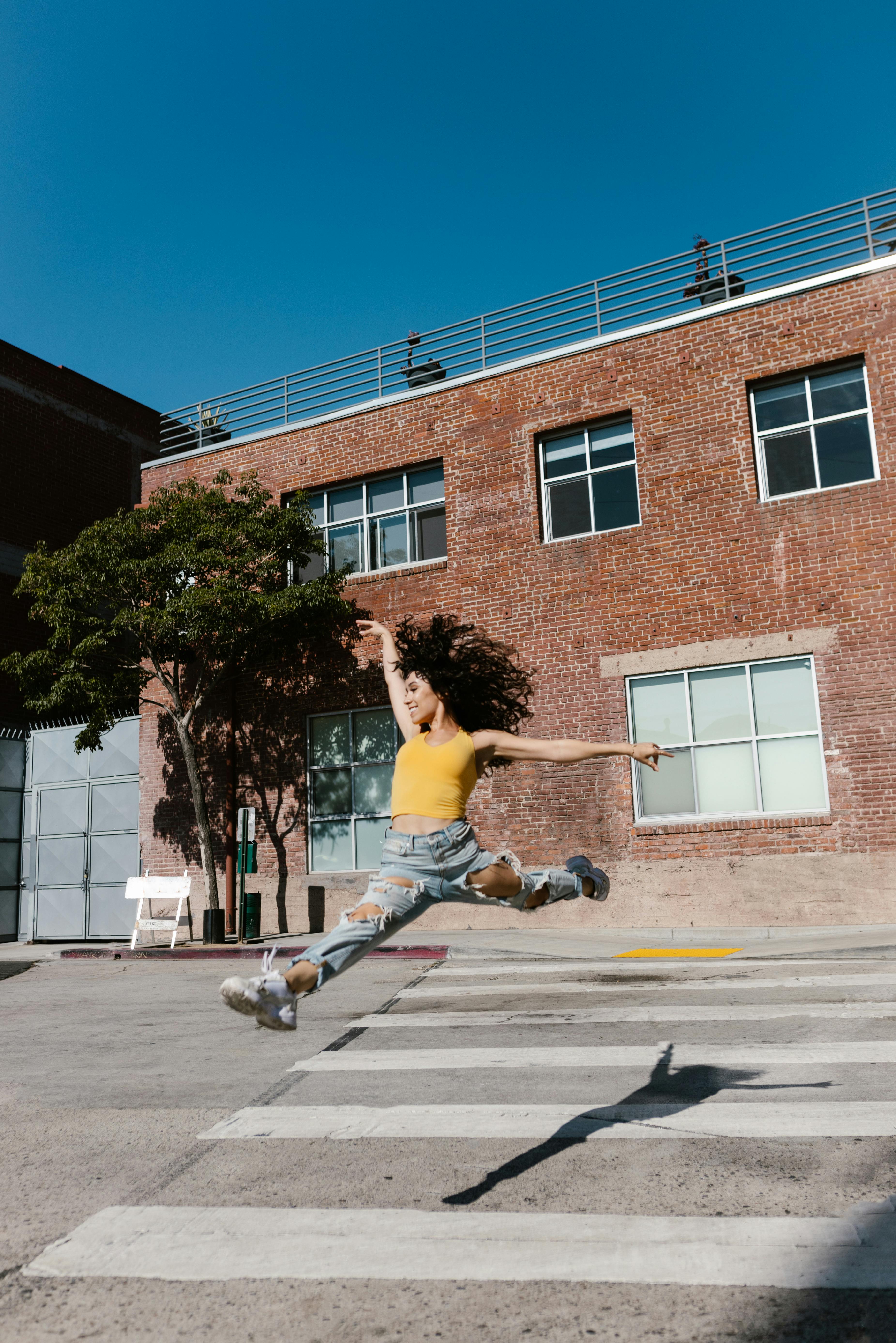 Woman in Yellow Tank Top and Blue Denim Shorts Dancing · Free Stock Photo