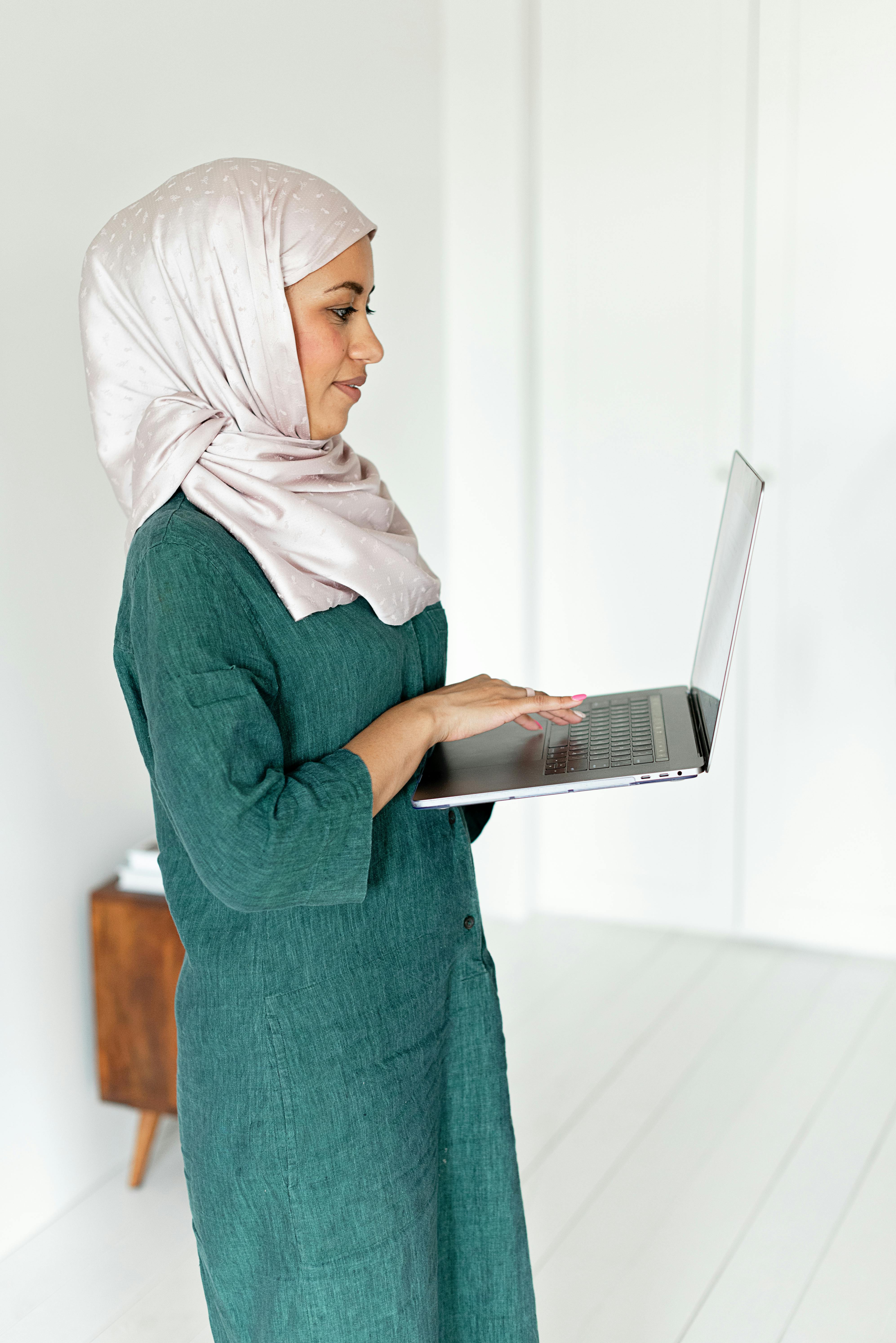 Woman Standing while Using Her Laptop · Free Stock Photo