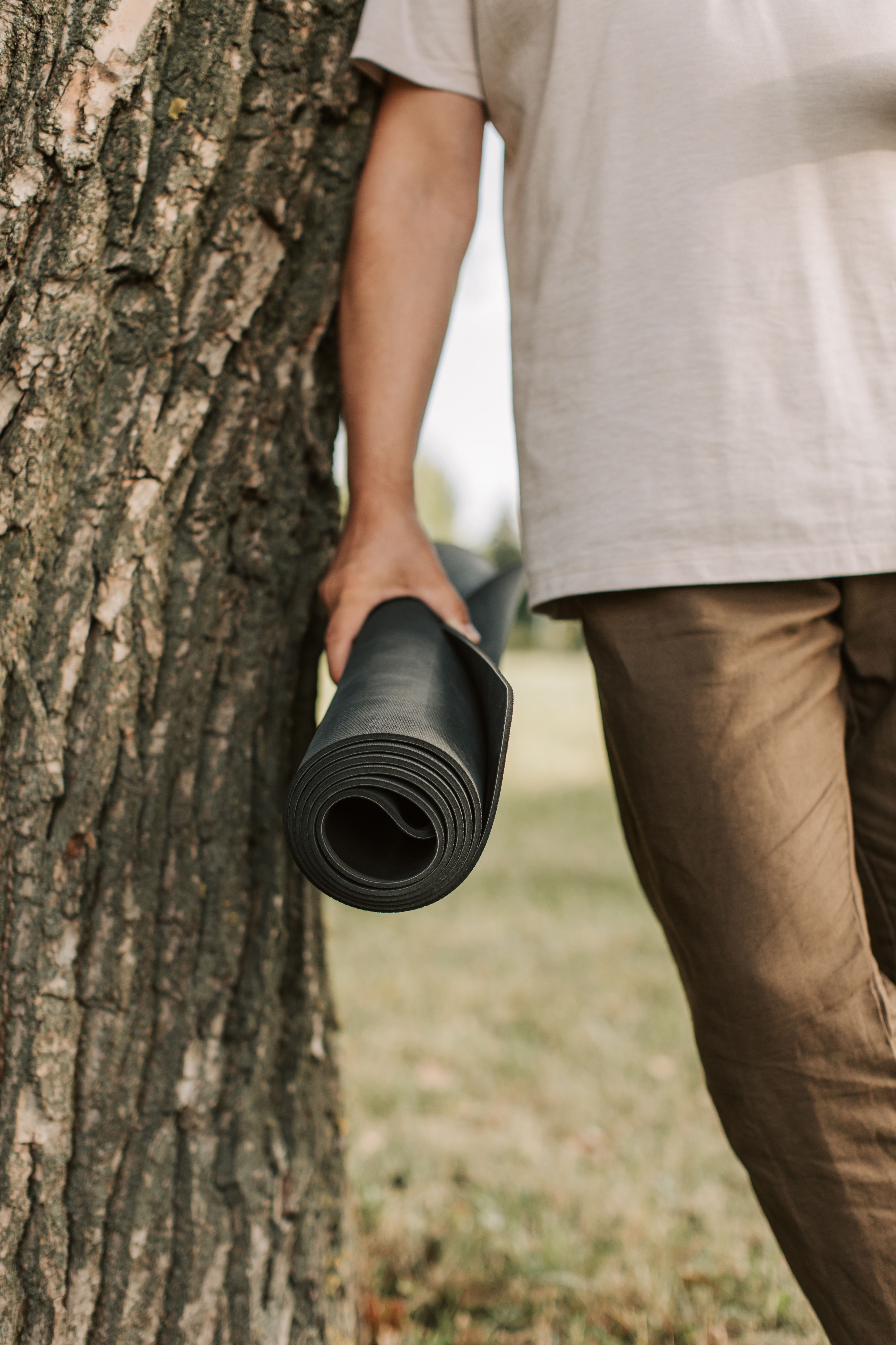 Close Up Shot of a Person Leaning on Tree Trunk While Holding Yoga Mat ...