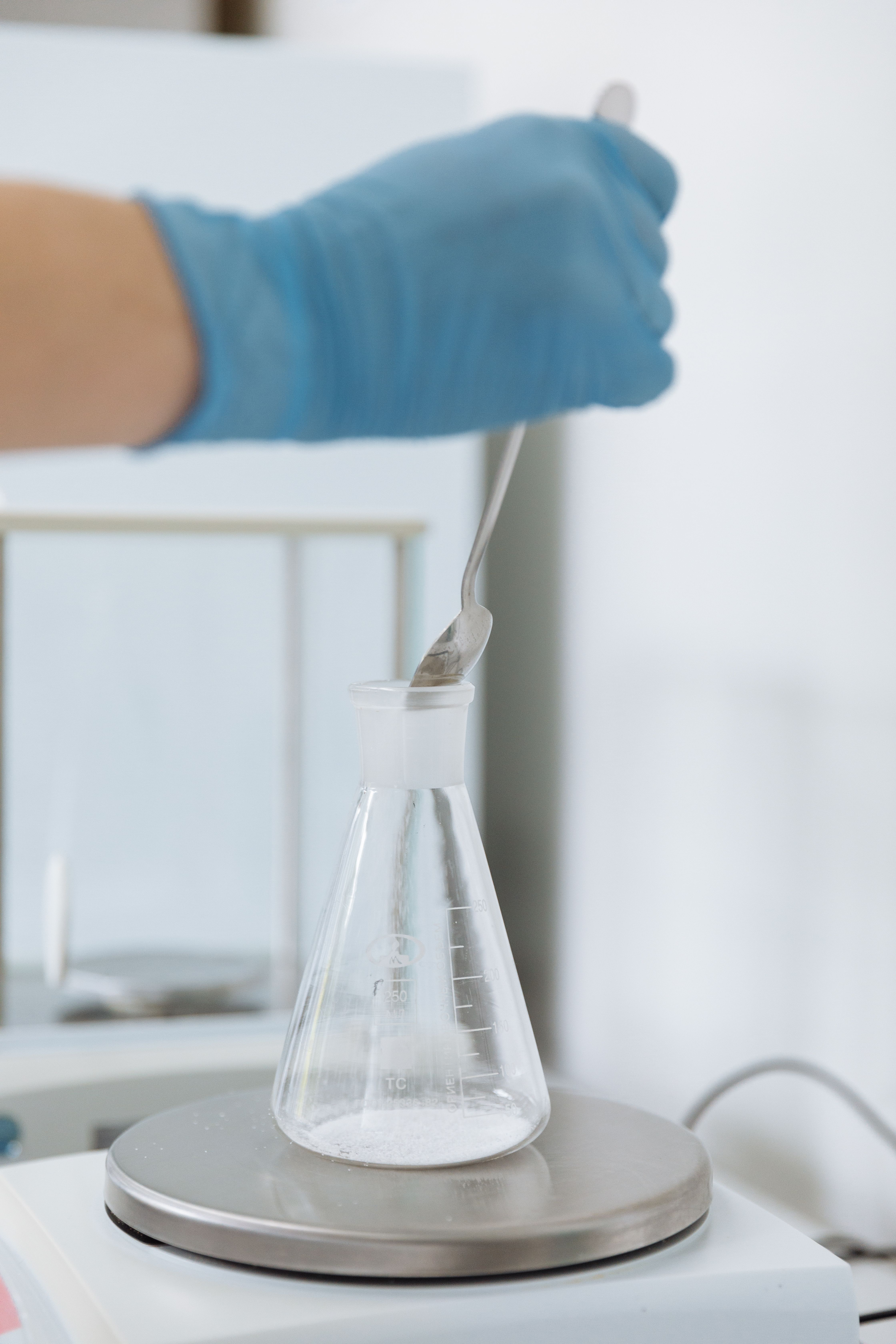 Crop chemist pouring clear liquid into fragile glassware in science ...