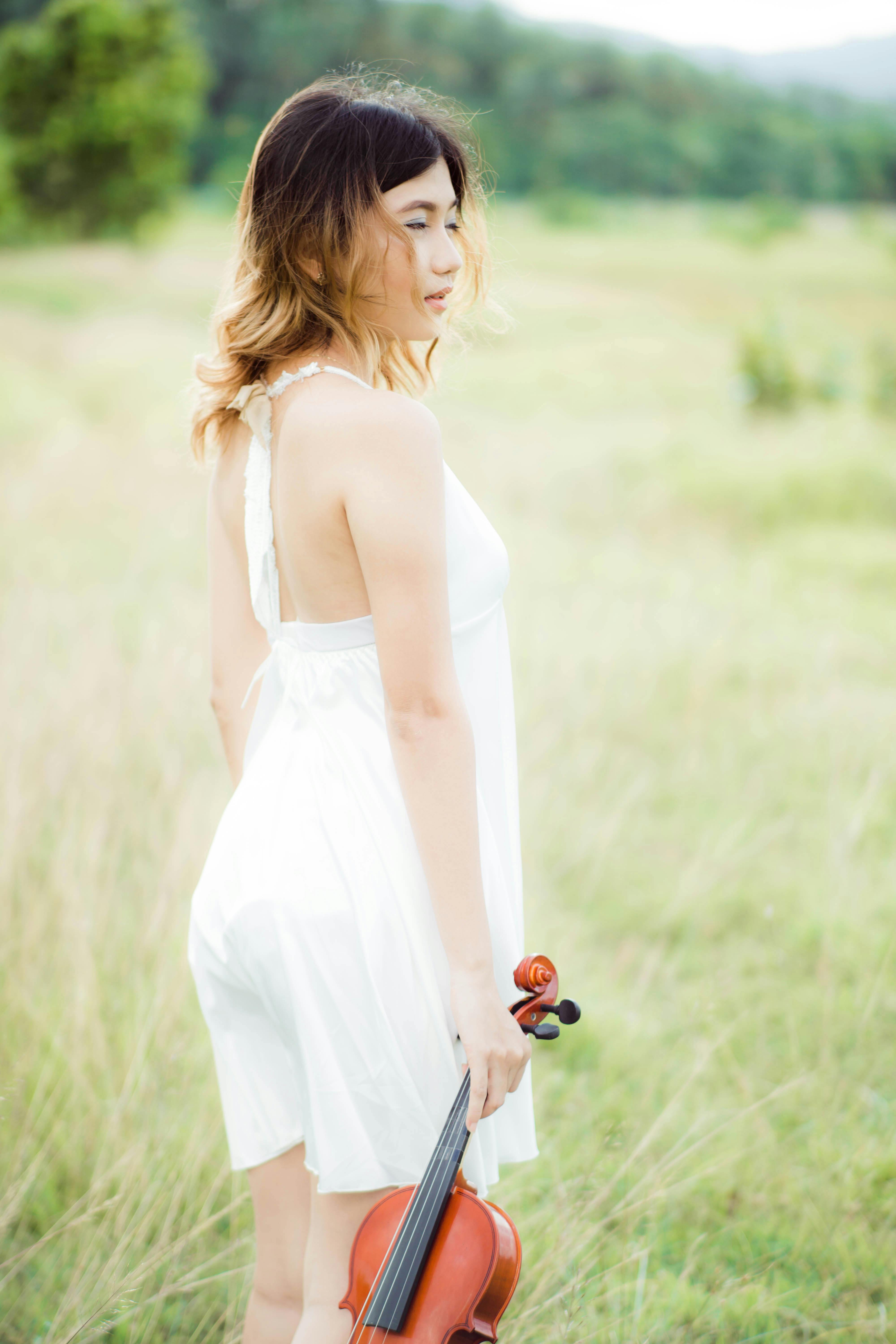 Woman Playing Violin White Resting on the Green Grass · Free Stock Photo