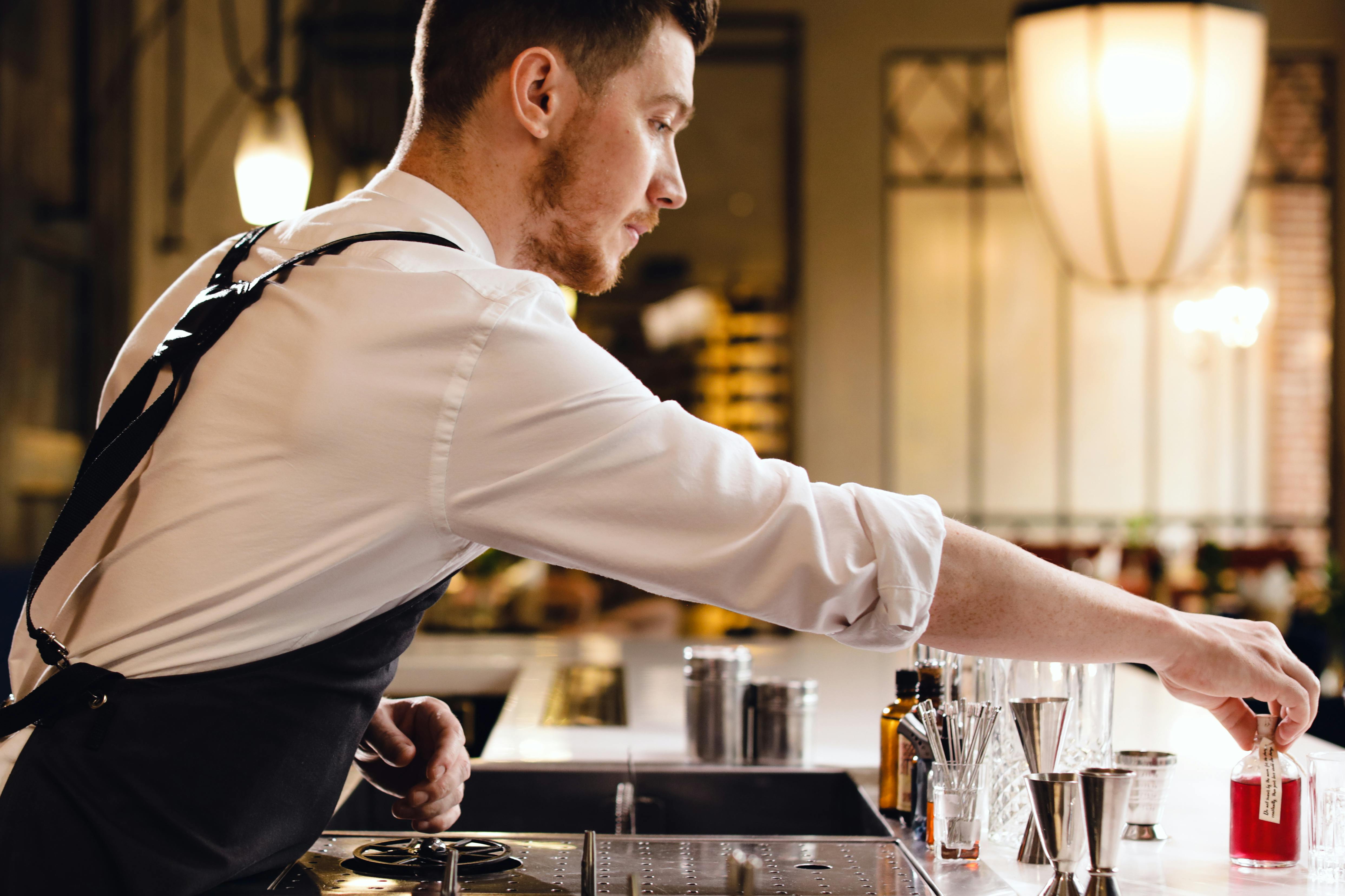 Side view of a Bartender Making a Drink at a Bar · Free Stock Photo