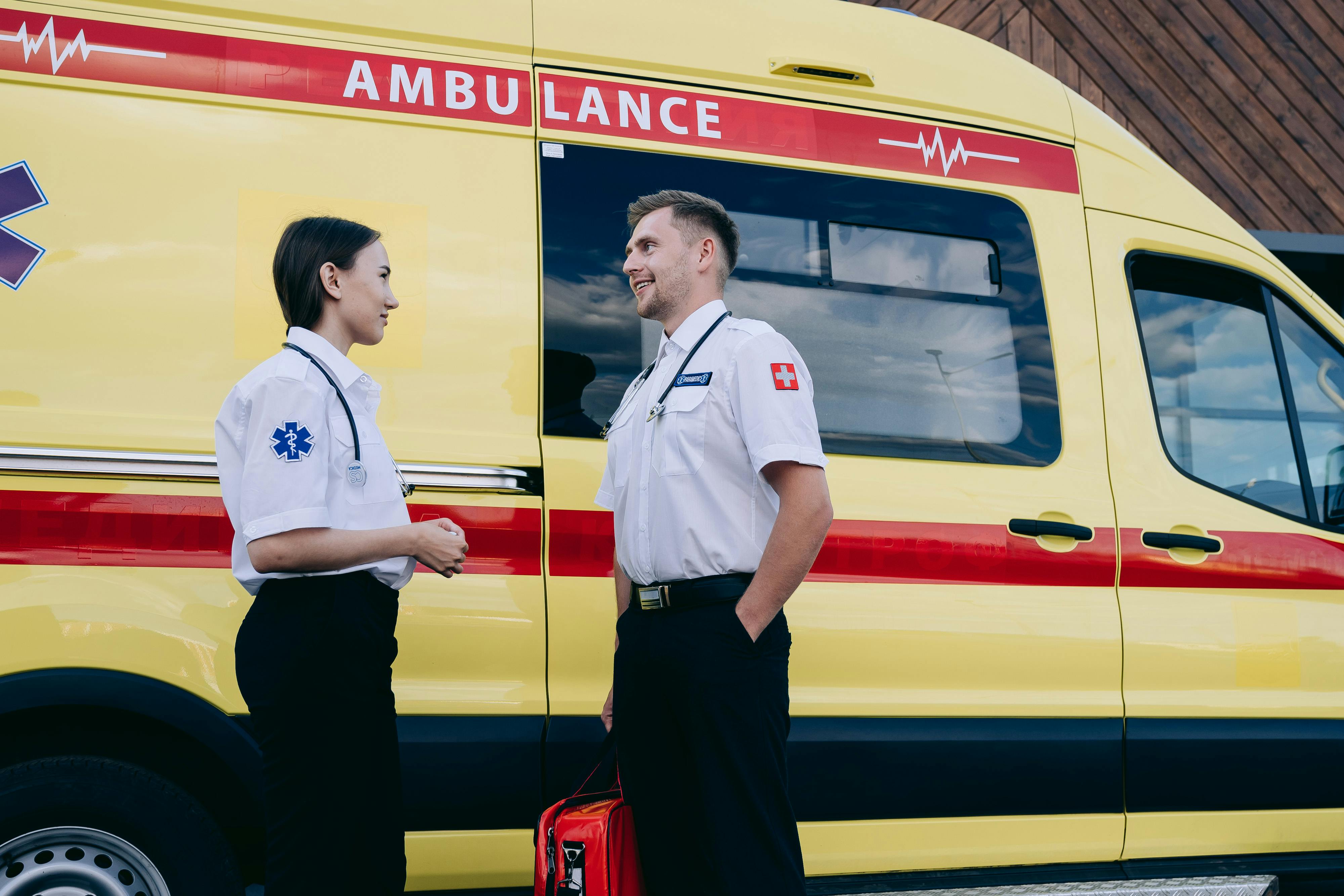Man and Woman Having Conversation Near an Ambulance · Free Stock Photo