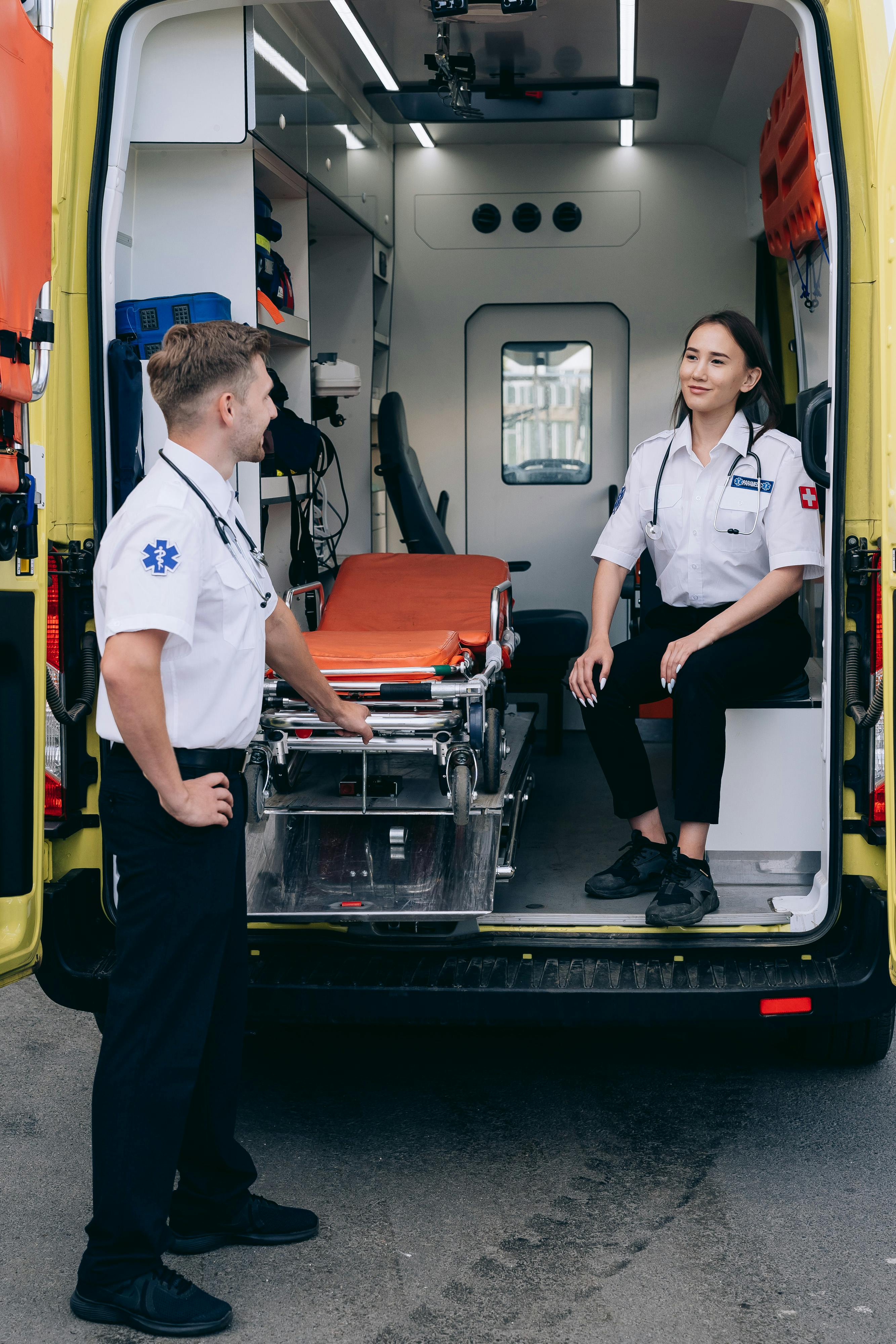 A Pair of Paramedics Beside a Stretcher in an Ambulance · Free Stock Photo