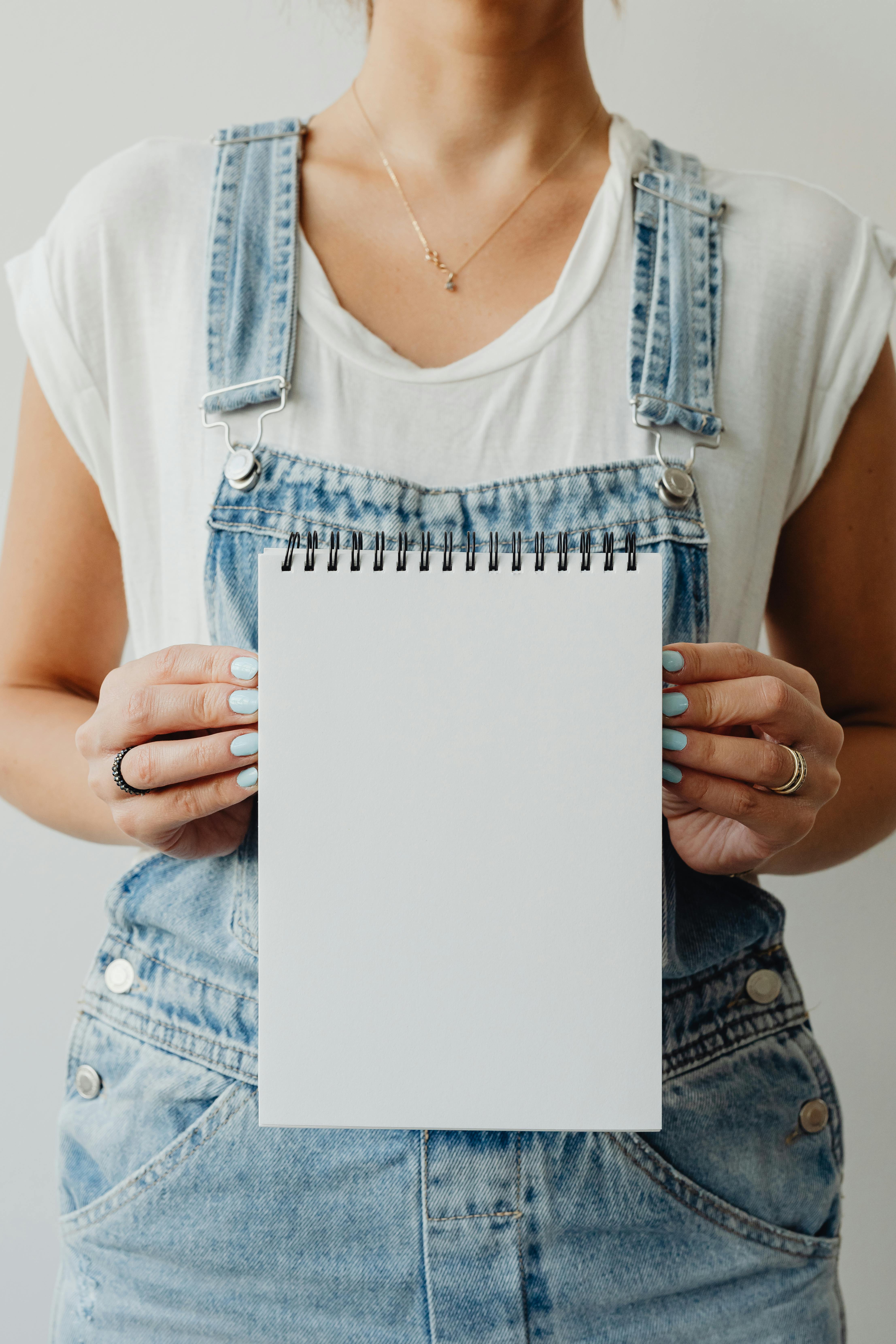 Woman in White Shirt Holding a Spiral Note Pad · Free Stock Photo