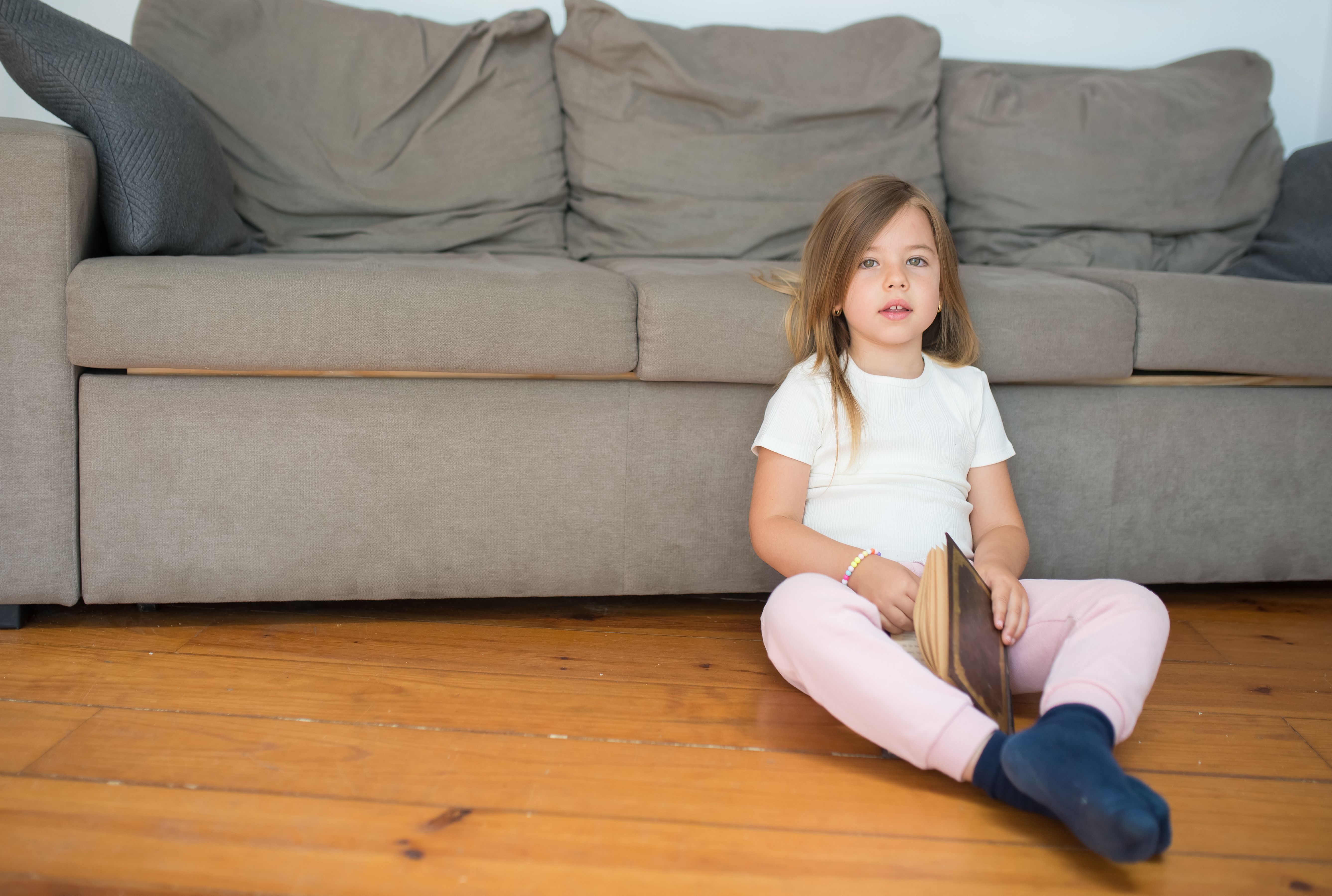 A Kid Sitting on the Floor While Holding a Book · Free Stock Photo