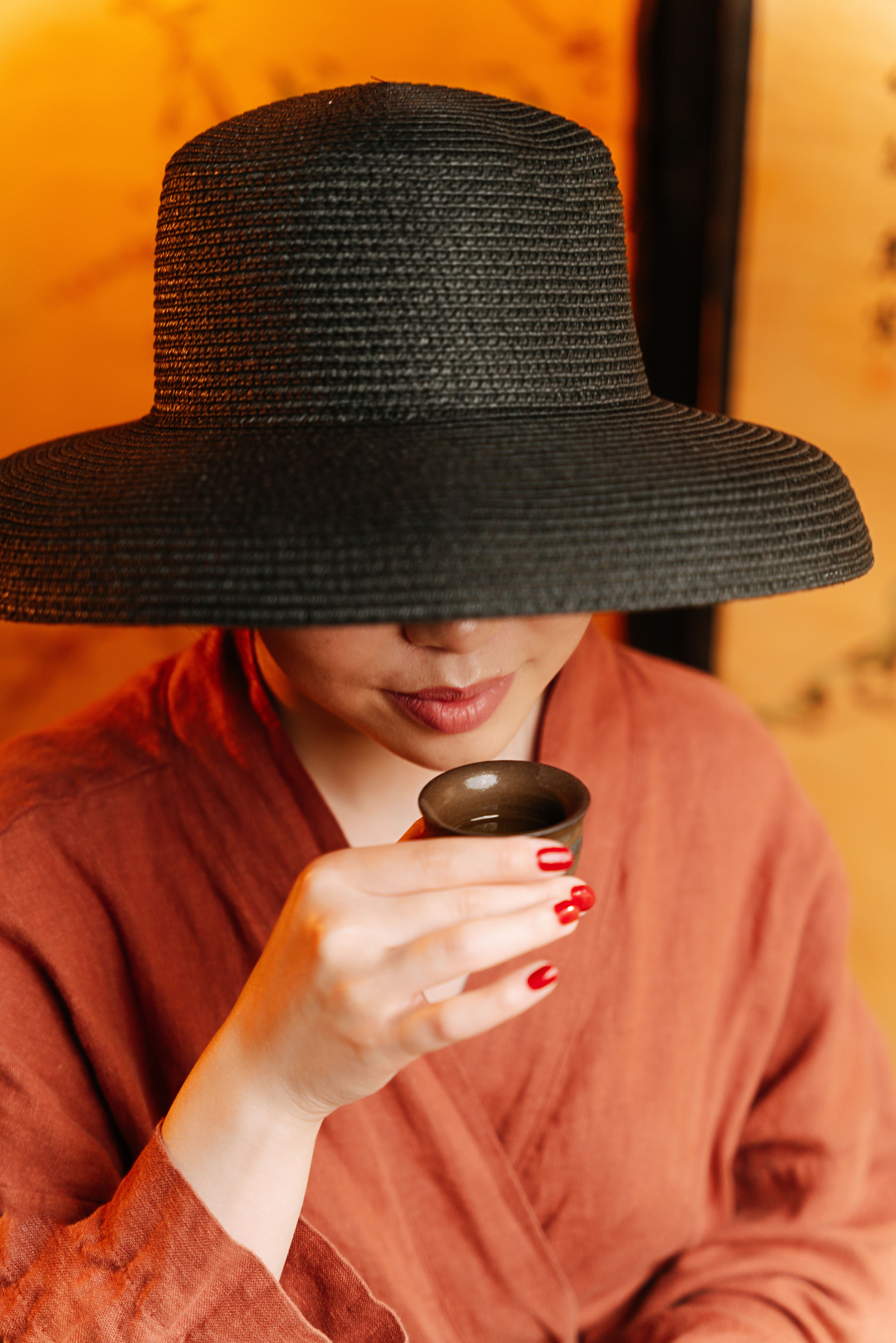 A Woman in Robe and Black Hat Drinking Tea · Free Stock Photo