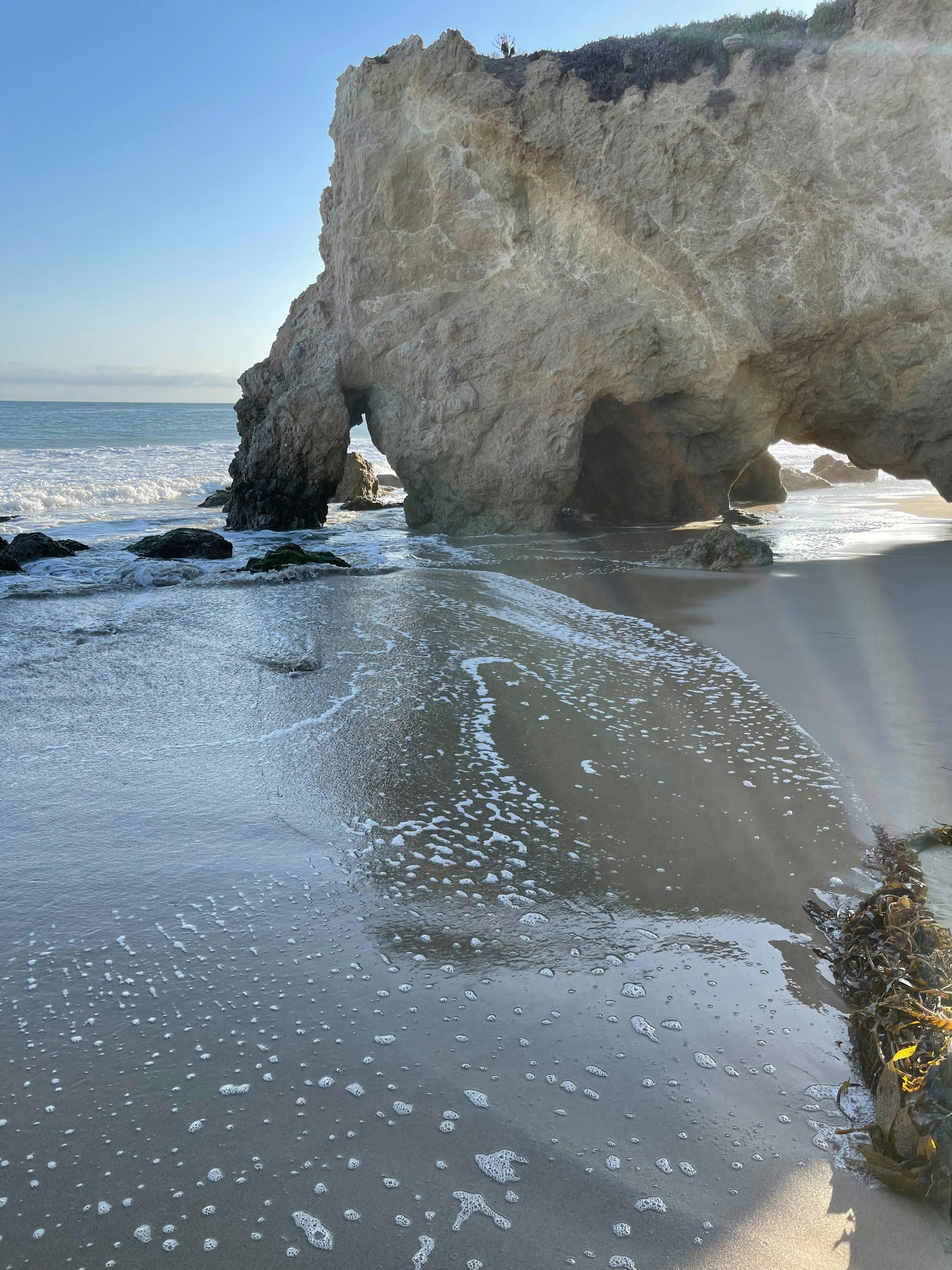 Sandy shore with rocky formations near ocean · Free Stock Photo