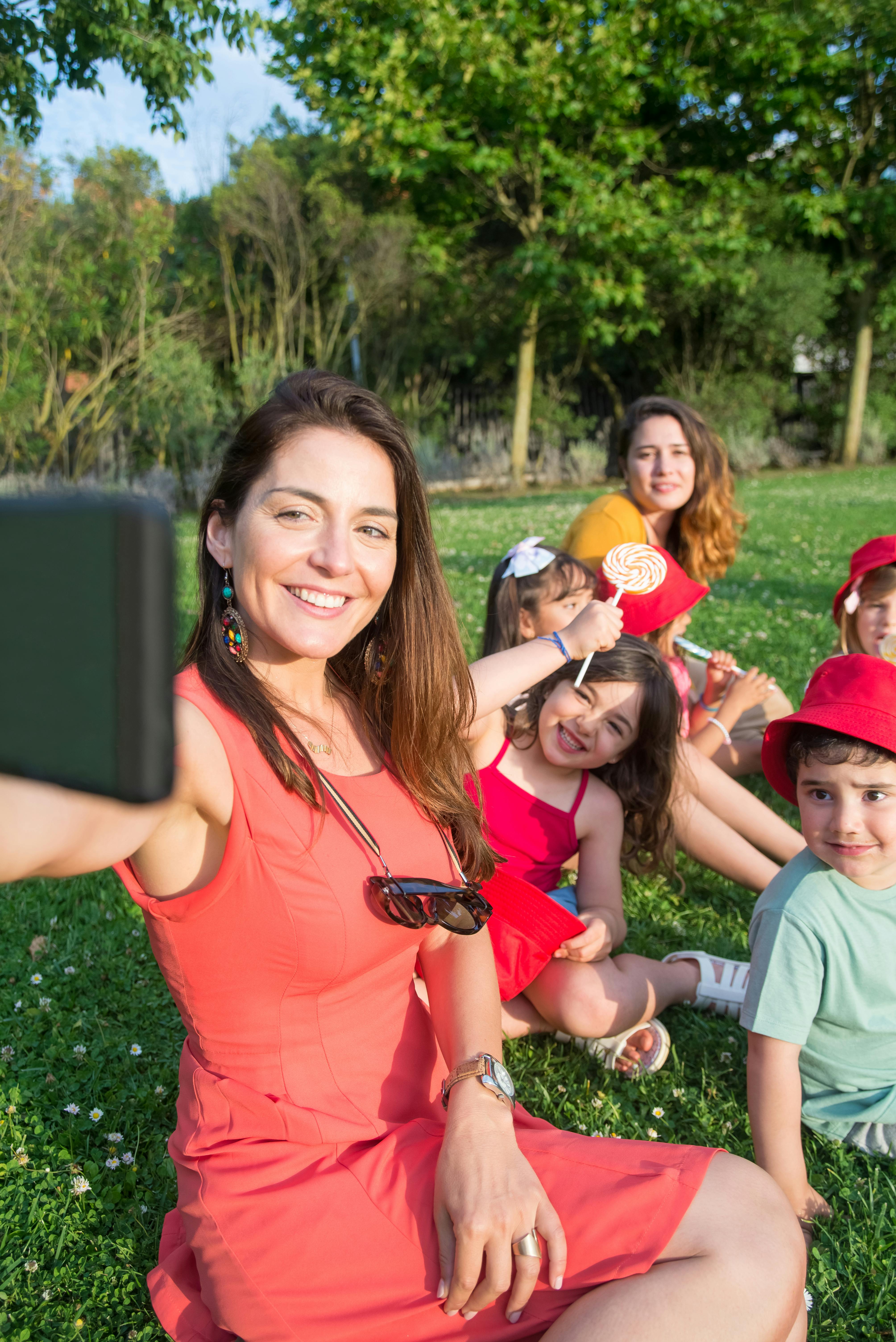 Woman Taking a Group Selfie while Sitting on Grass · Free Stock Photo
