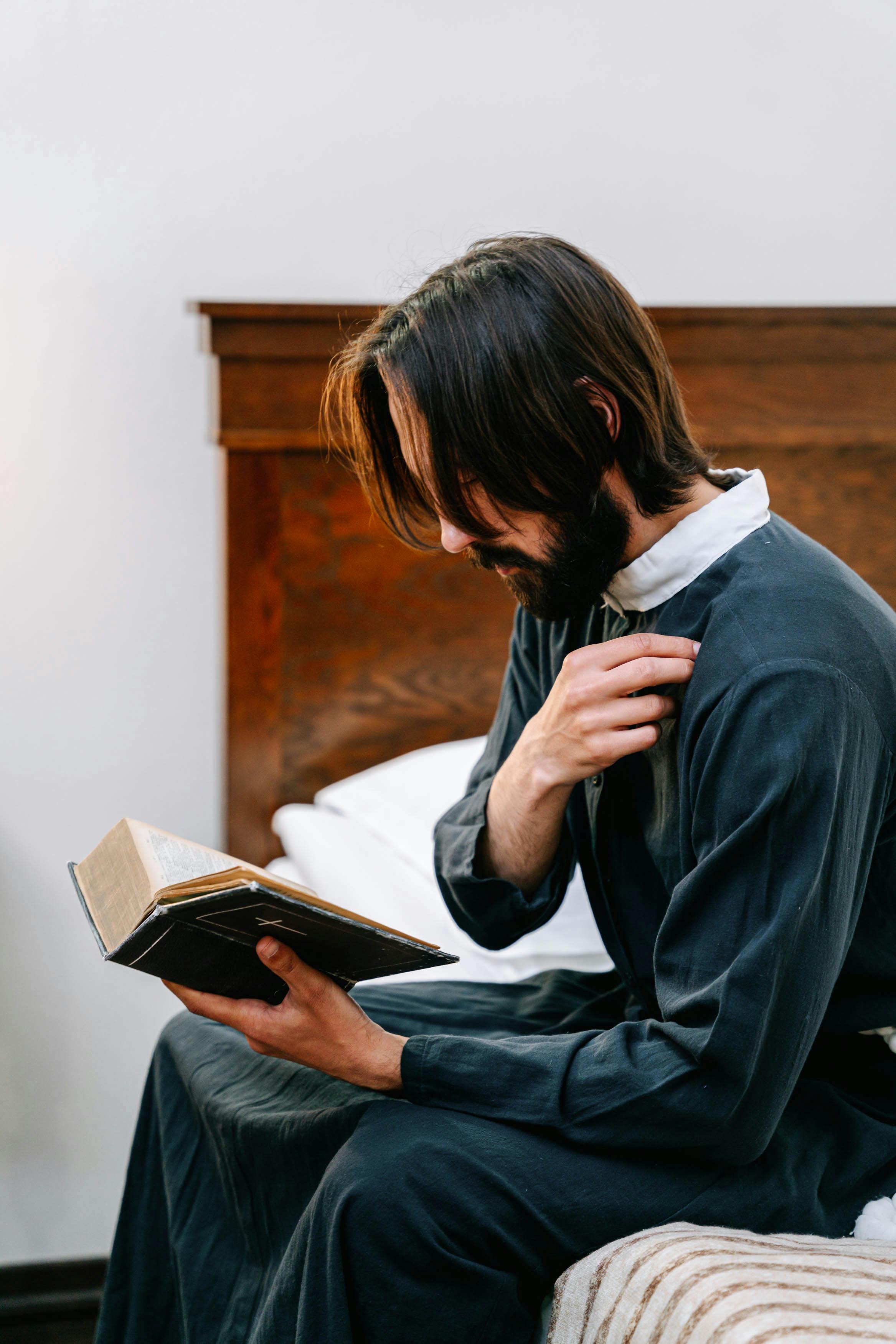 A Bearded Man in Blue Robe Holding a Bible Making Sign of the Cross ...