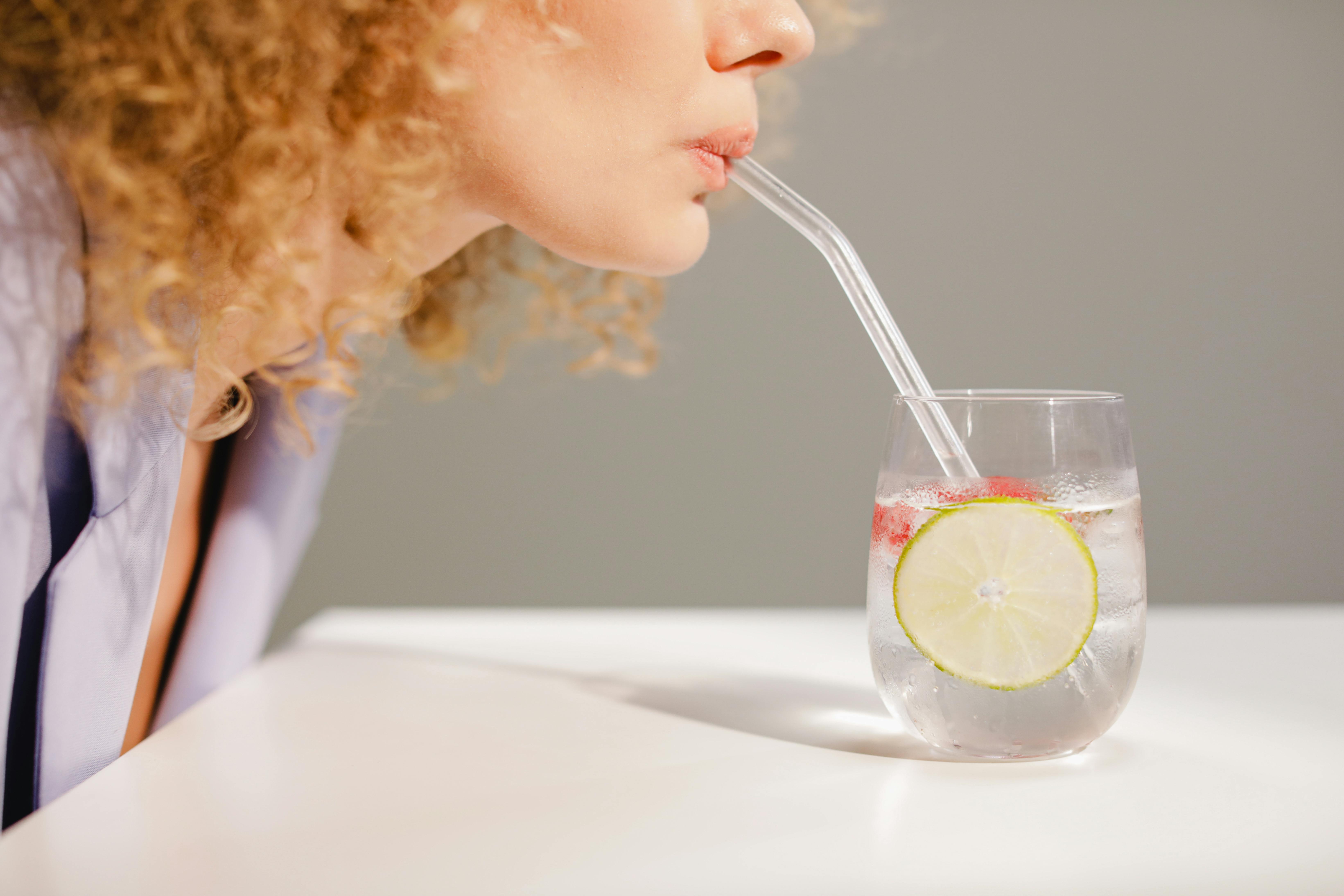 Woman Sipping from Clear Glass With Antioxidant Drink · Free Stock Photo