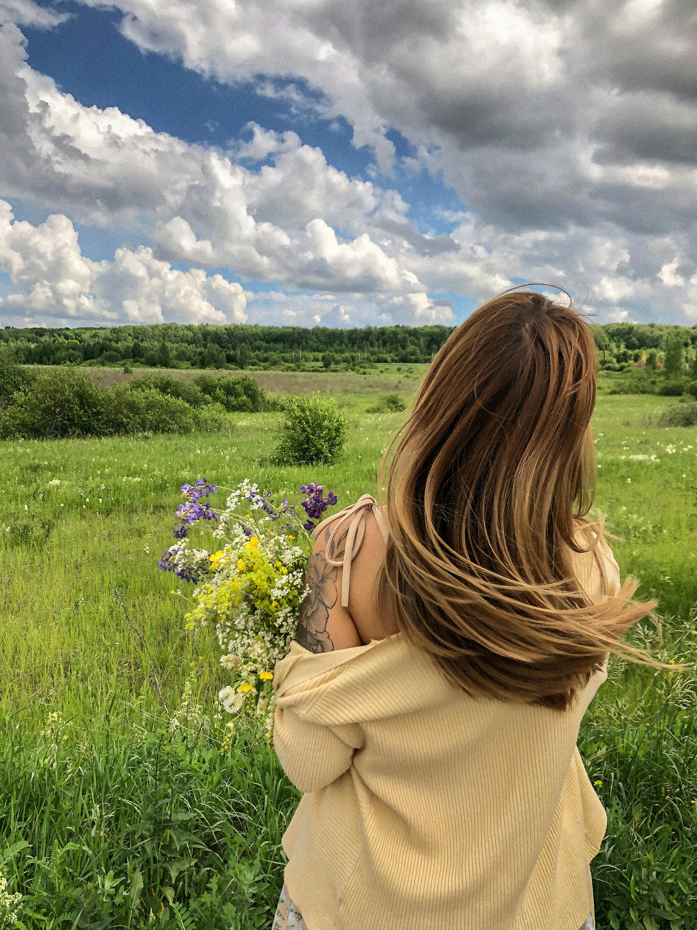 Back View of Brunette Woman Holding a Bunch of Flowers · Free Stock Photo