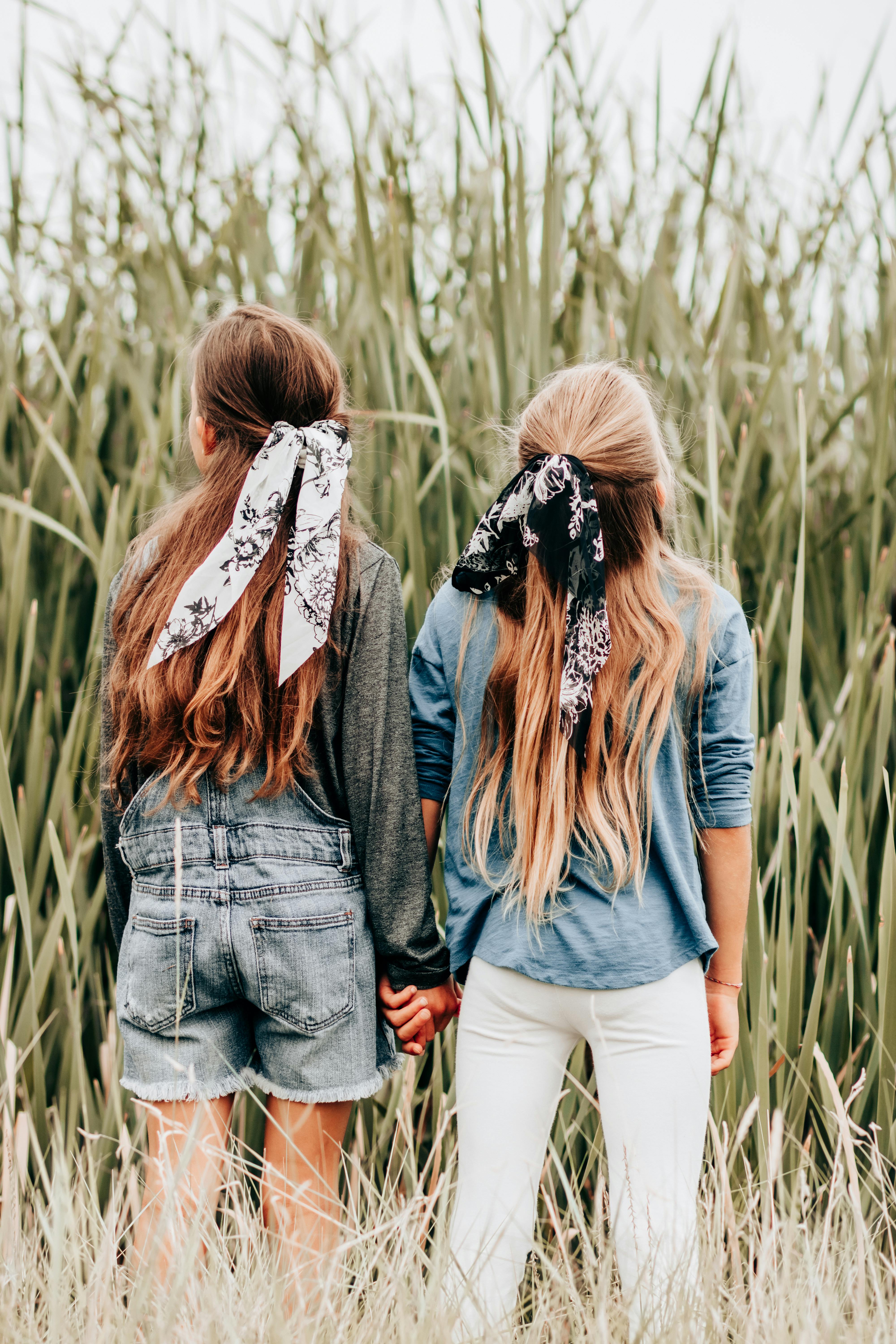 Back View of Two Girls Standing on Grass Field · Free Stock Photo