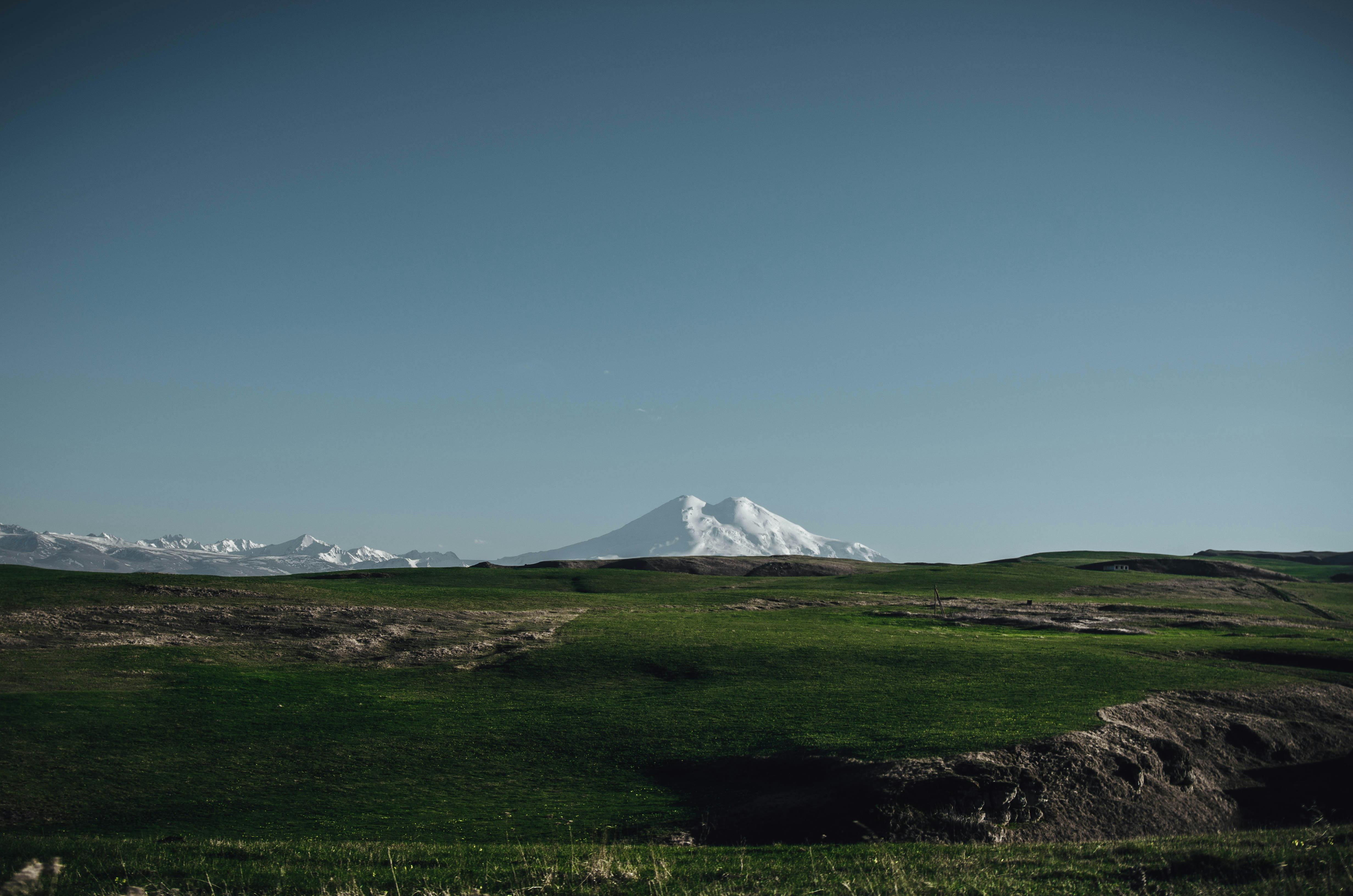 Green Grass Field Near Snow Covered Mountain Under Blue Sky · Free ...
