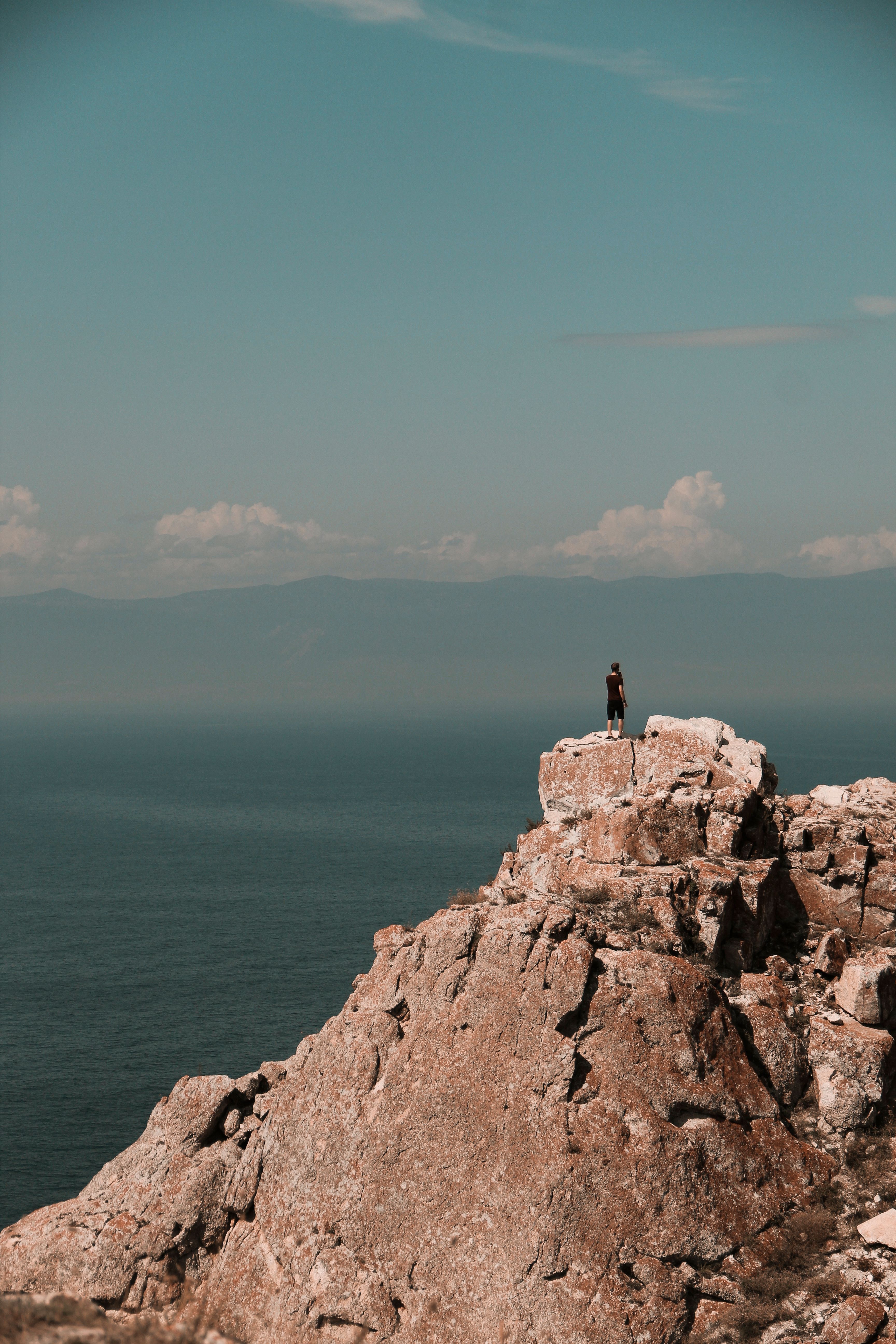 Person Standing On A Cliff Near Body of Water · Free Stock Photo