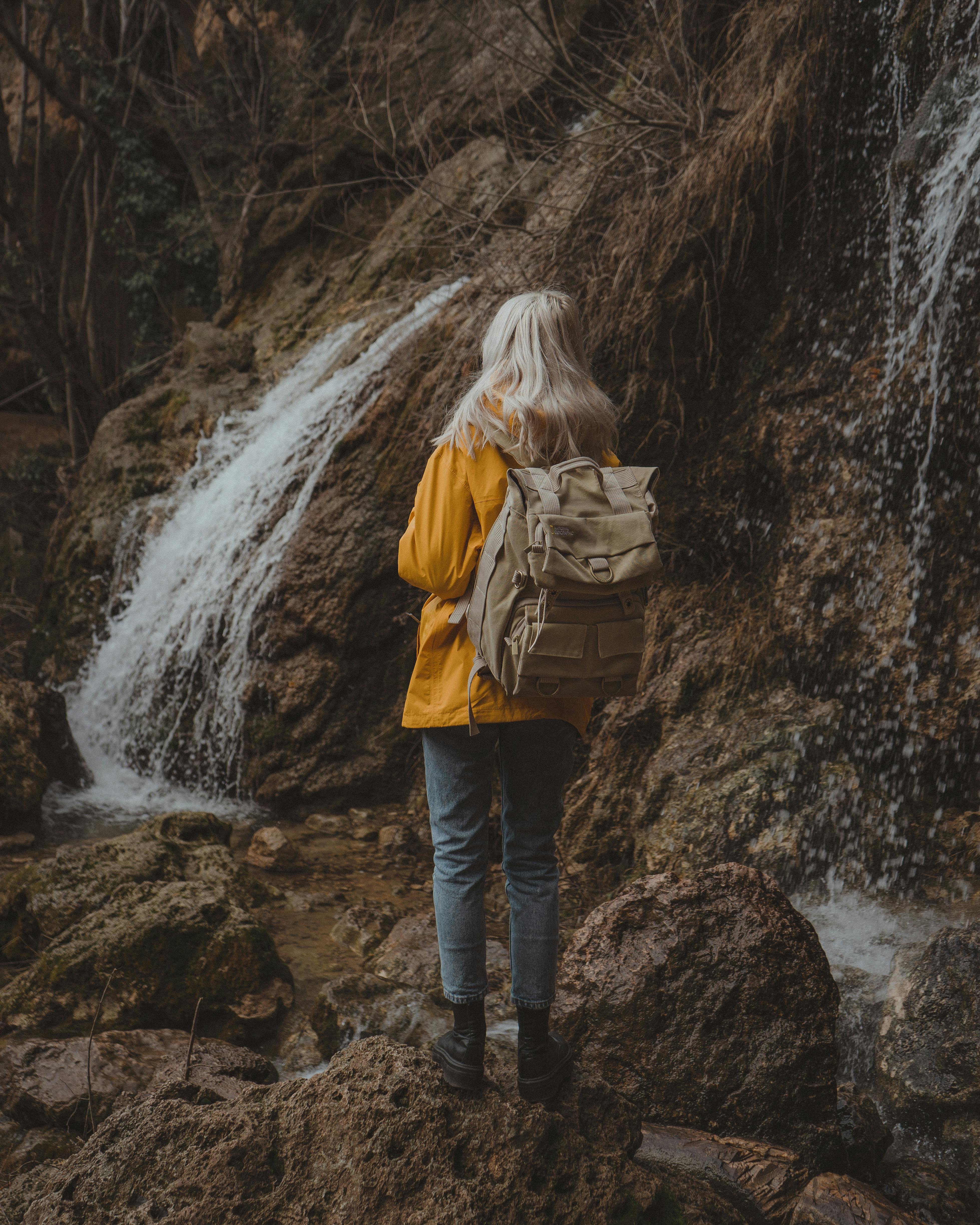 A Man Carrying Blue Backpack Standing on Big Rock while Looking at the ...