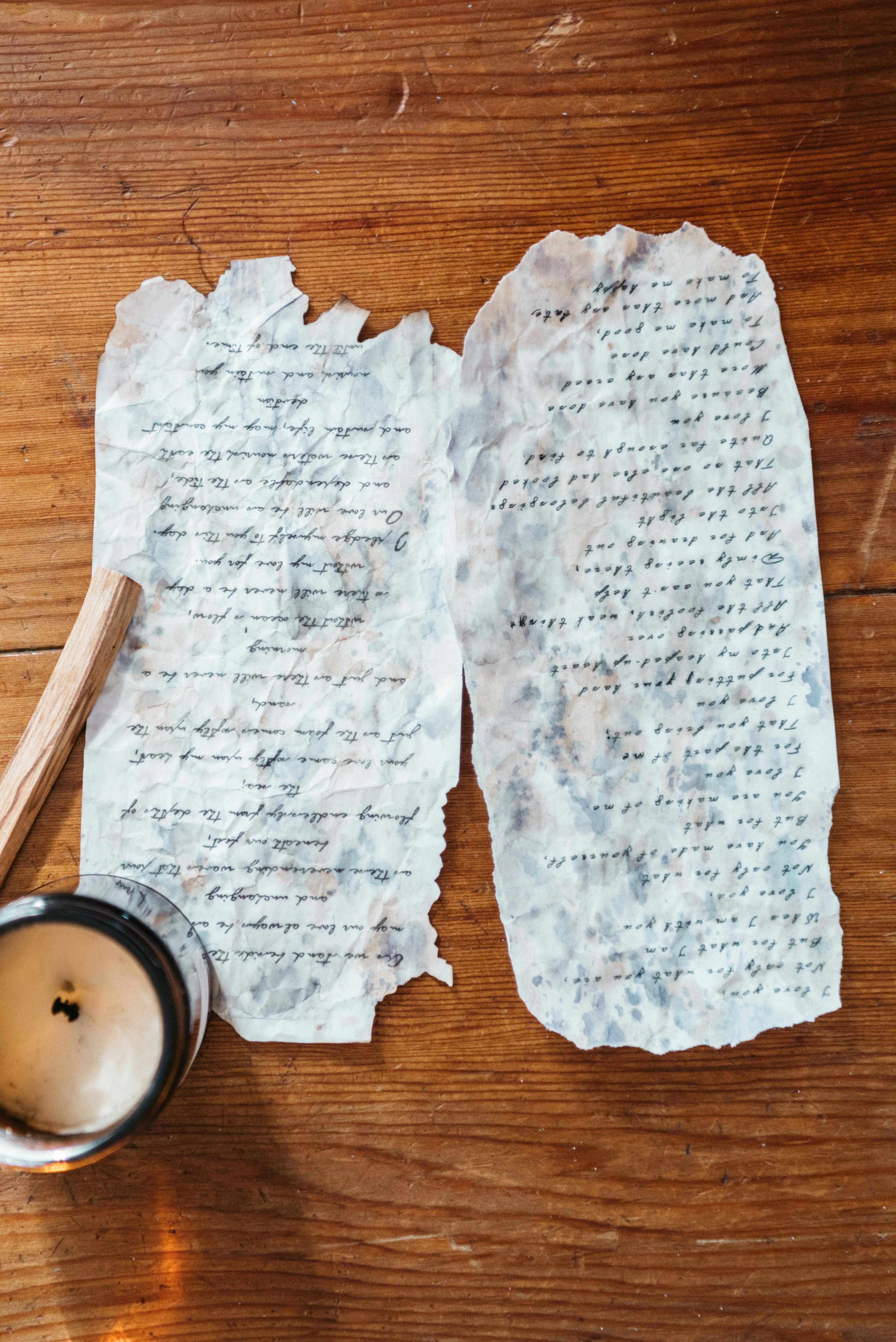 A Pair of Burnt Papers with Text Under a Candle on a Wooden Table ...